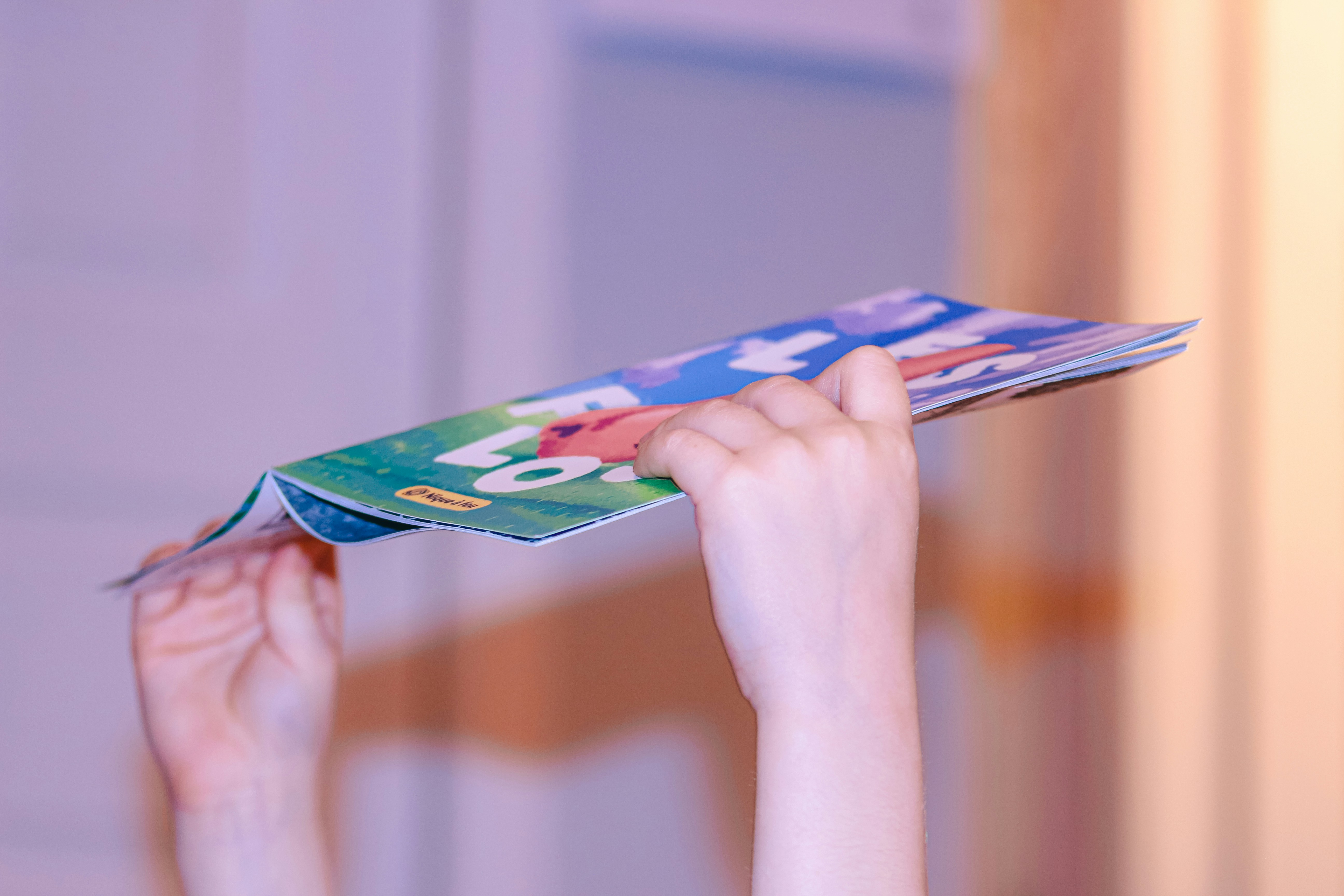 Child holding open a colorful book with illustrations. photo – Free ...