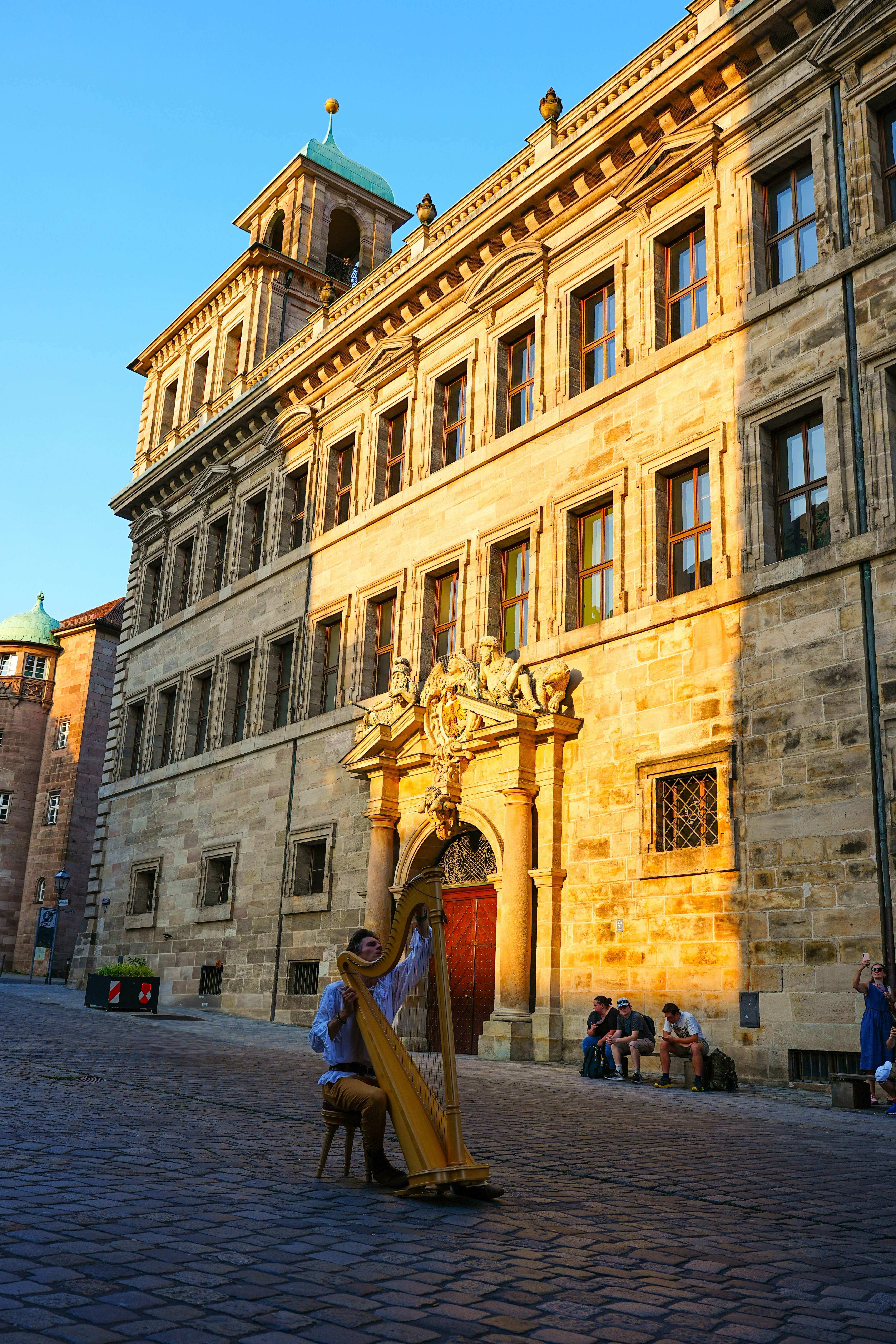 Man playing harp outside historic stone building