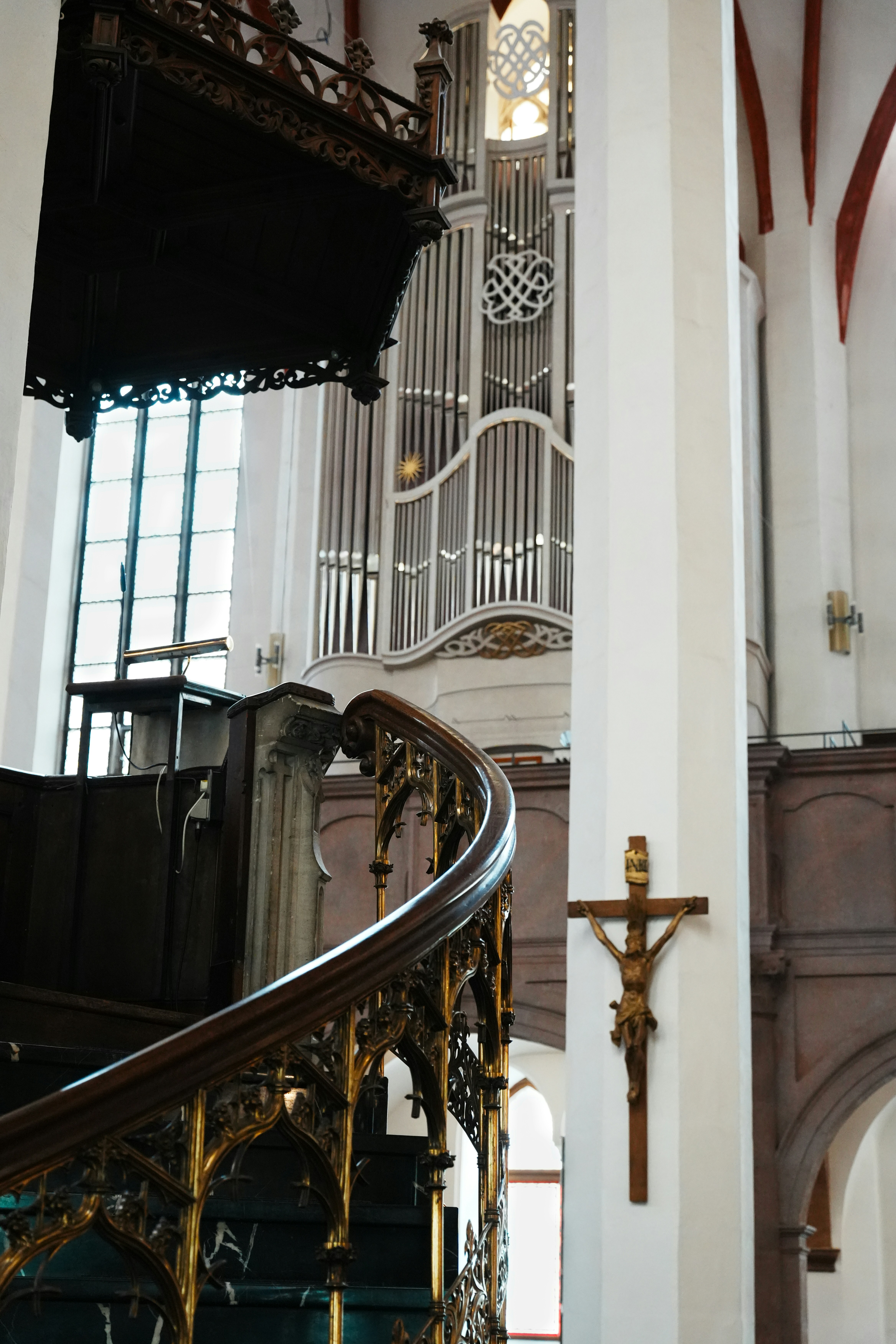 Curving Baroque railing leads the eye toward the organ pipes and crucifix