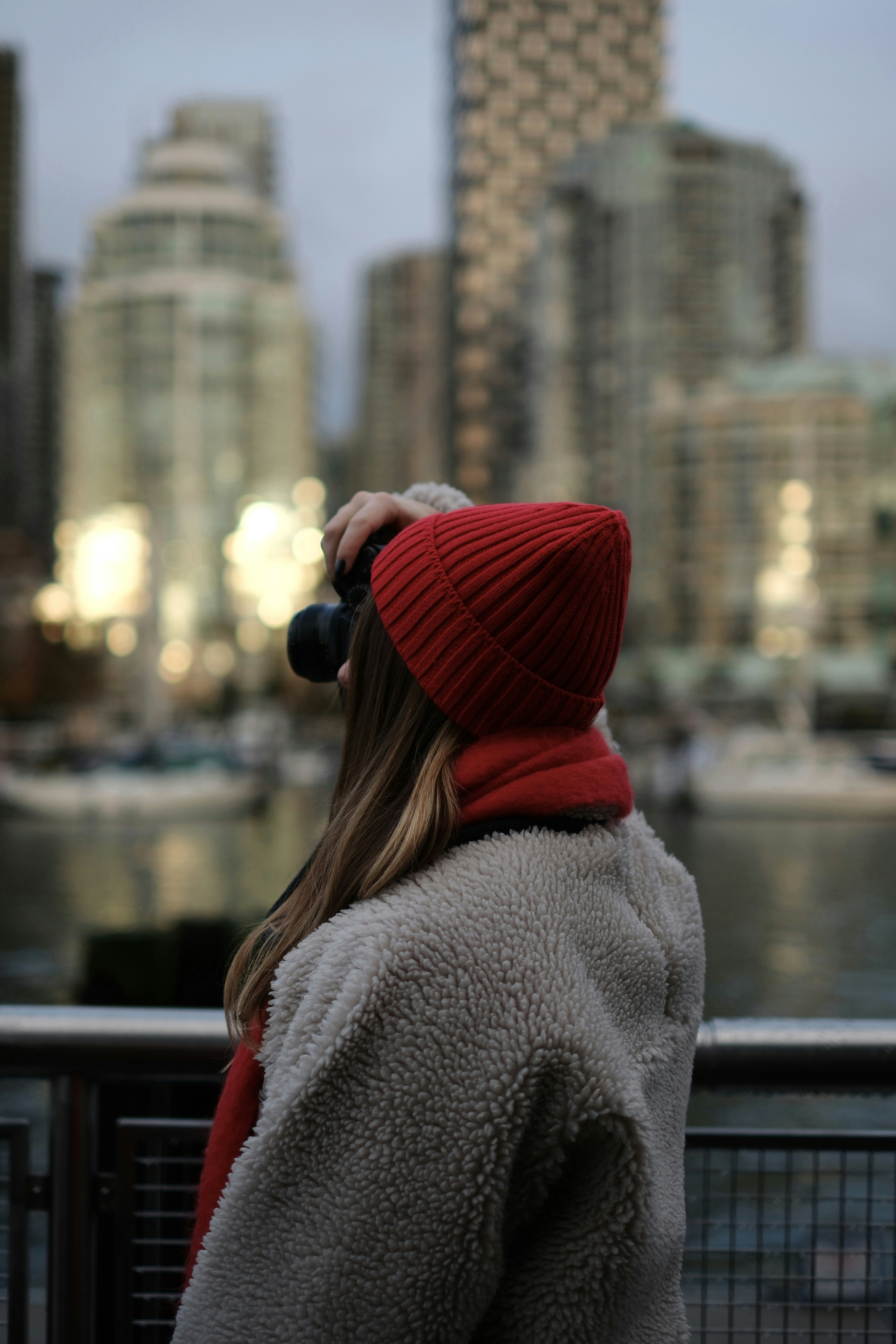 Red Beanie, Camera in Hand, City Lights as Backdrop