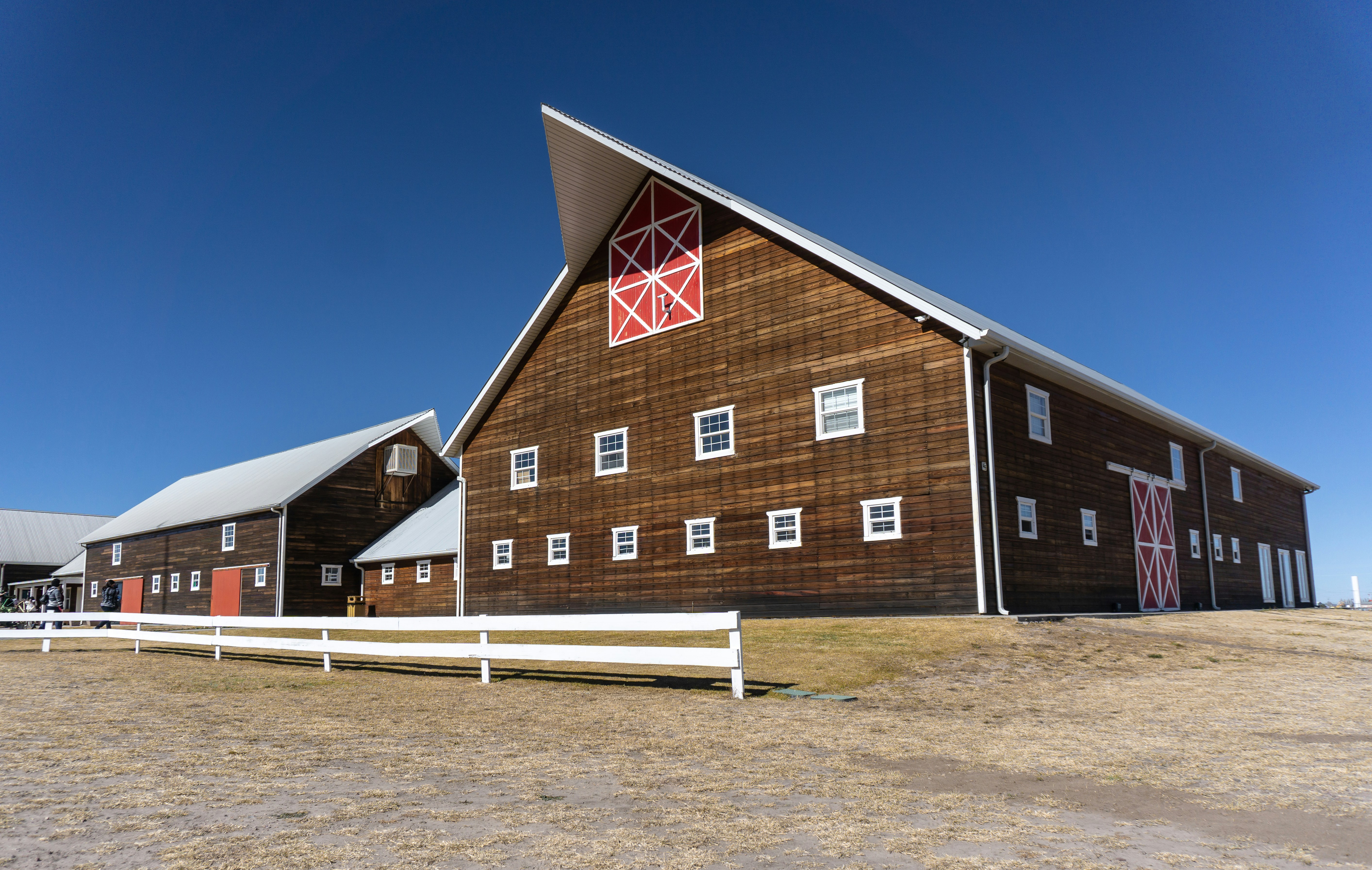 Barns on the Horizon: Red Doors and White Rails under Wide Sky