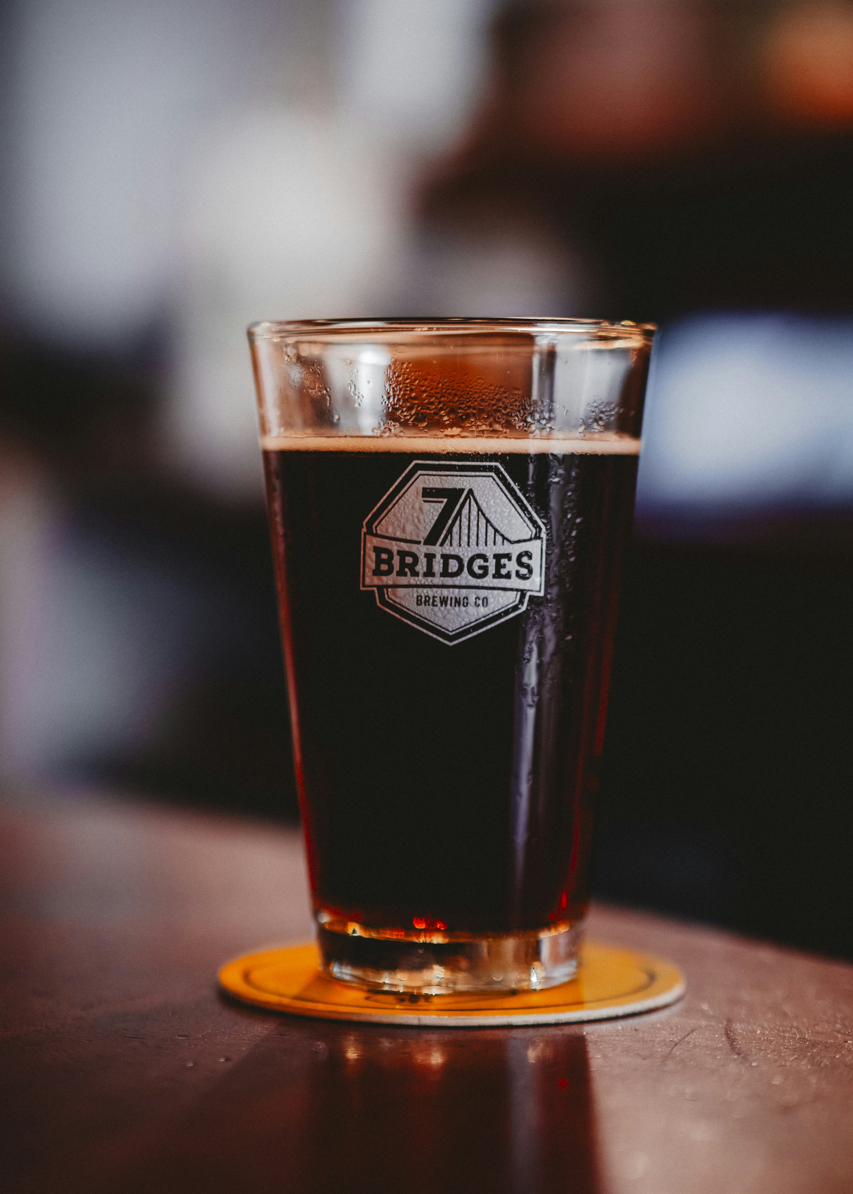 Glass of Dark Brew with Branded Glass on a Bar Top