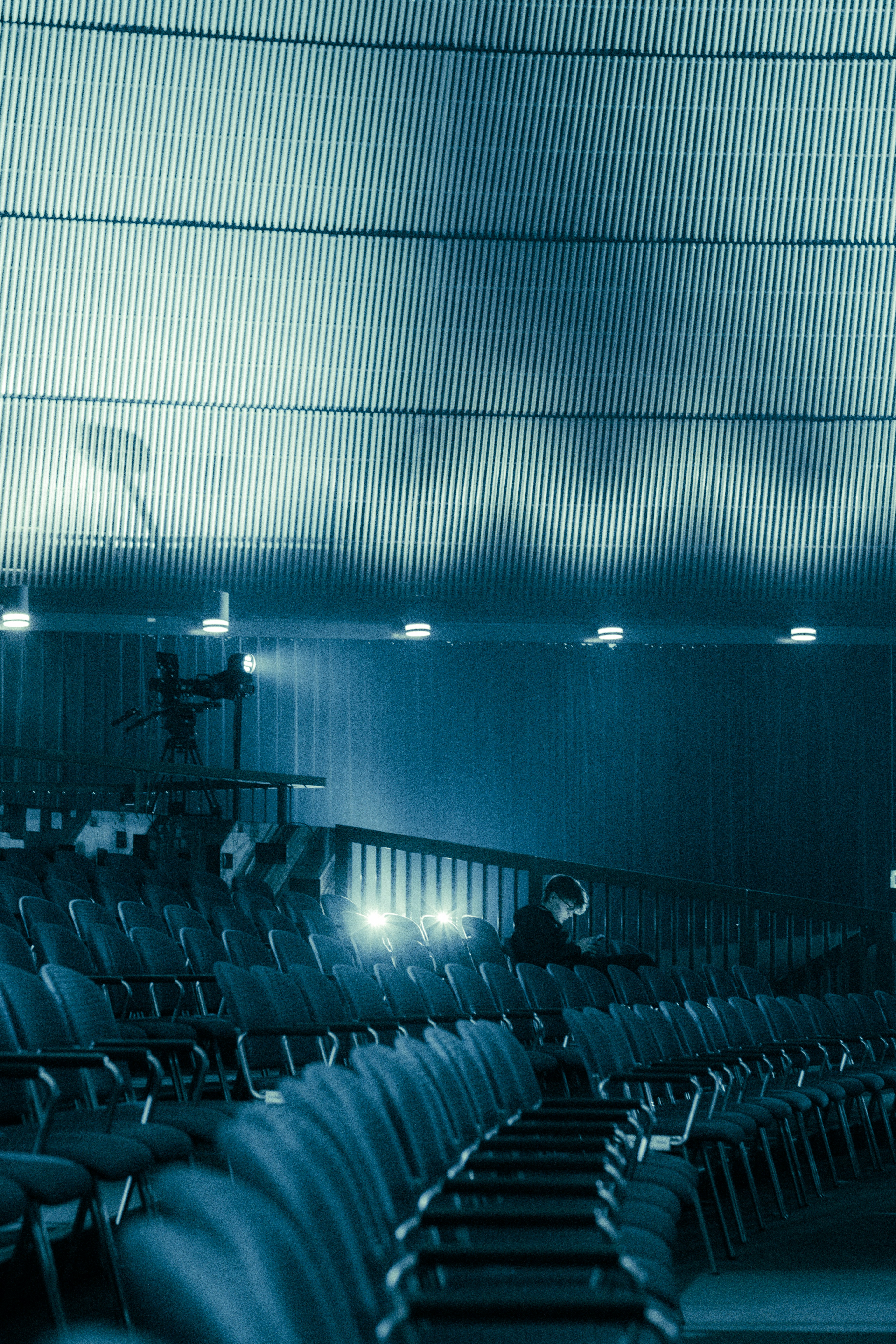 Blue Auditorium Quiet: A lone technician beside the row of seats under blue lighting