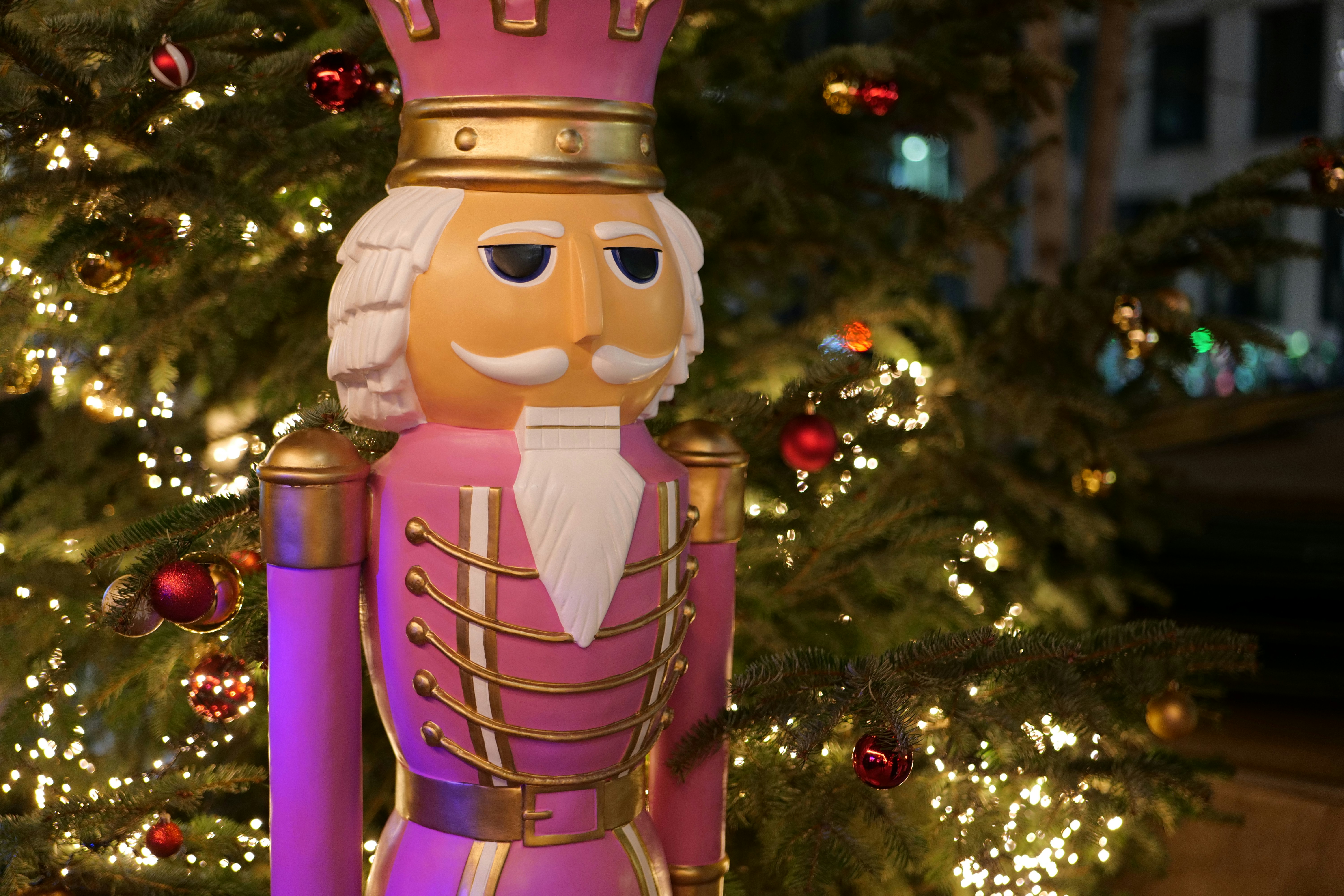 A pink nutcracker stands in front of a christmas tree. photo – Free ...