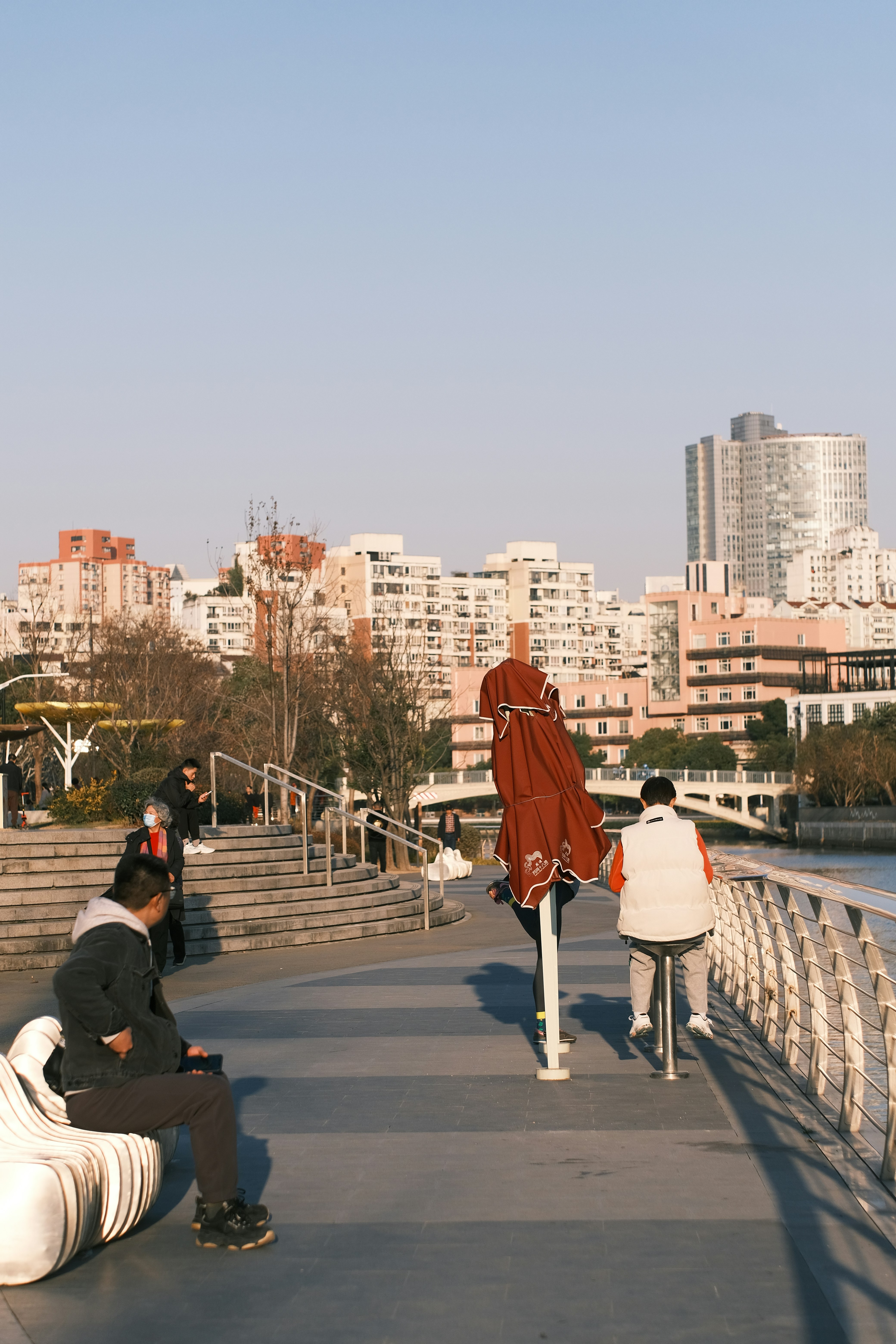 City Waterfront Promenade with Red Parasol and Urban Horizon