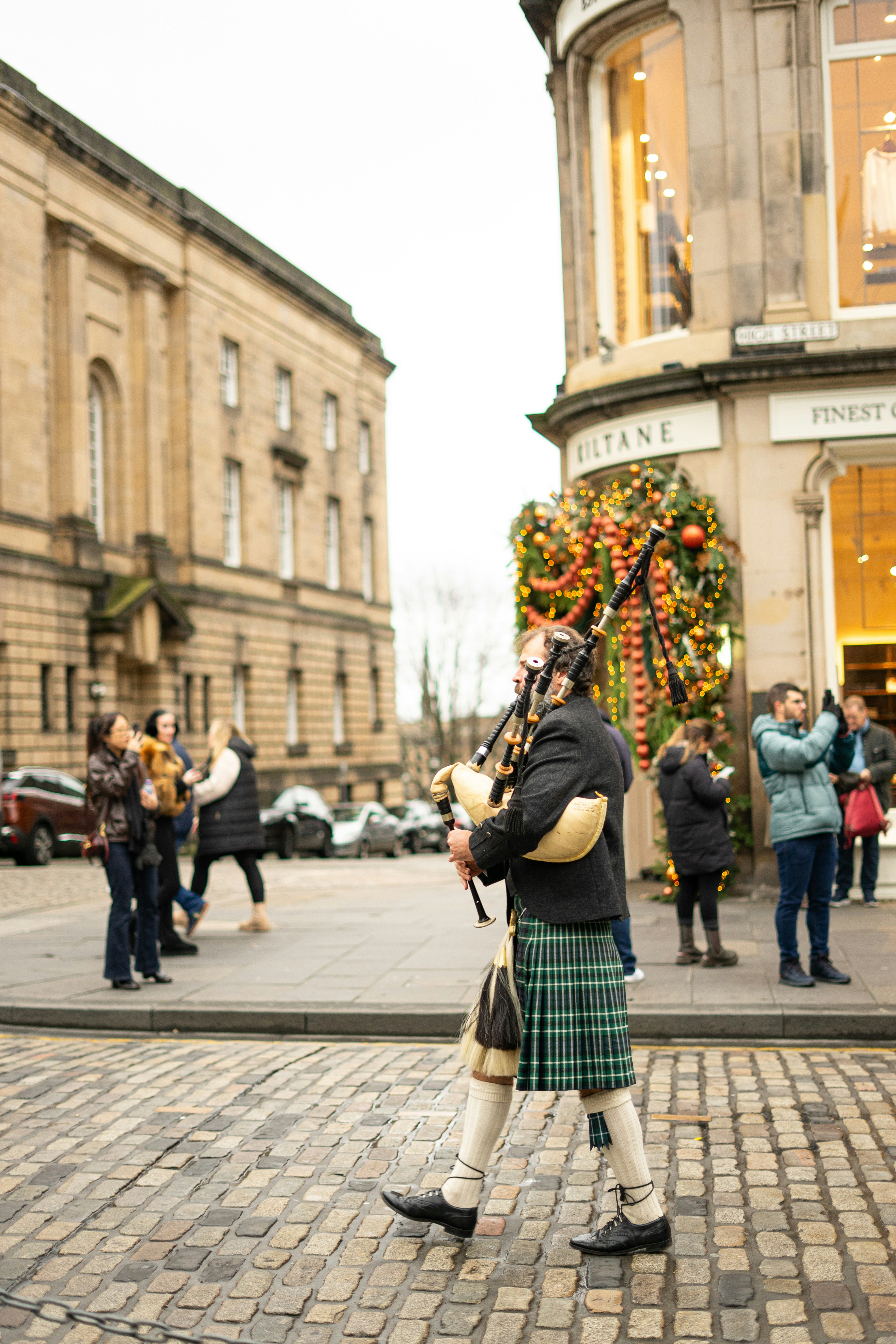 Piper in the Town: A Bagpiper Steps Through a Christmas-Decorated Street