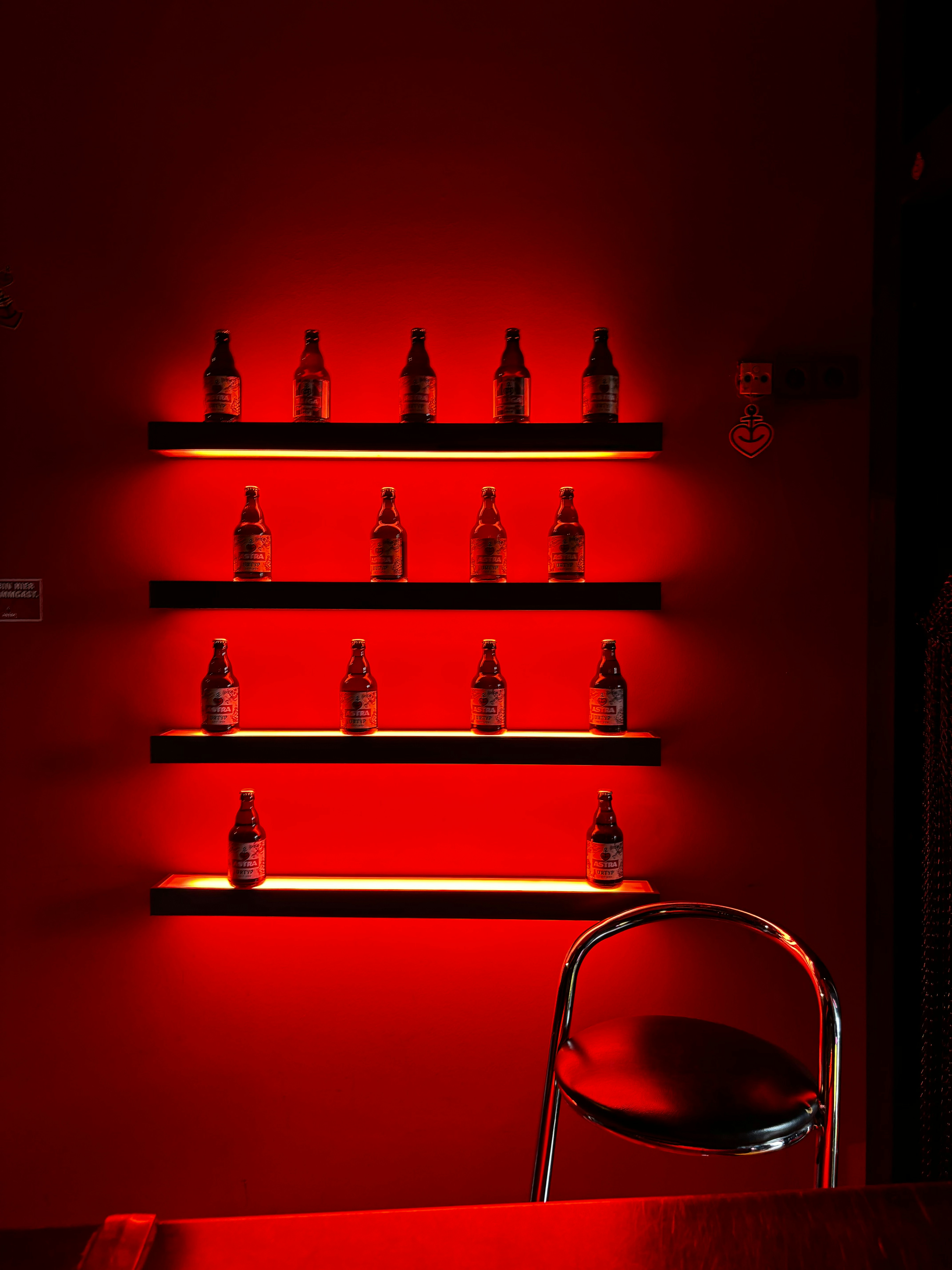 Red Shelf Echoes: Bottles on a Backlit Wall