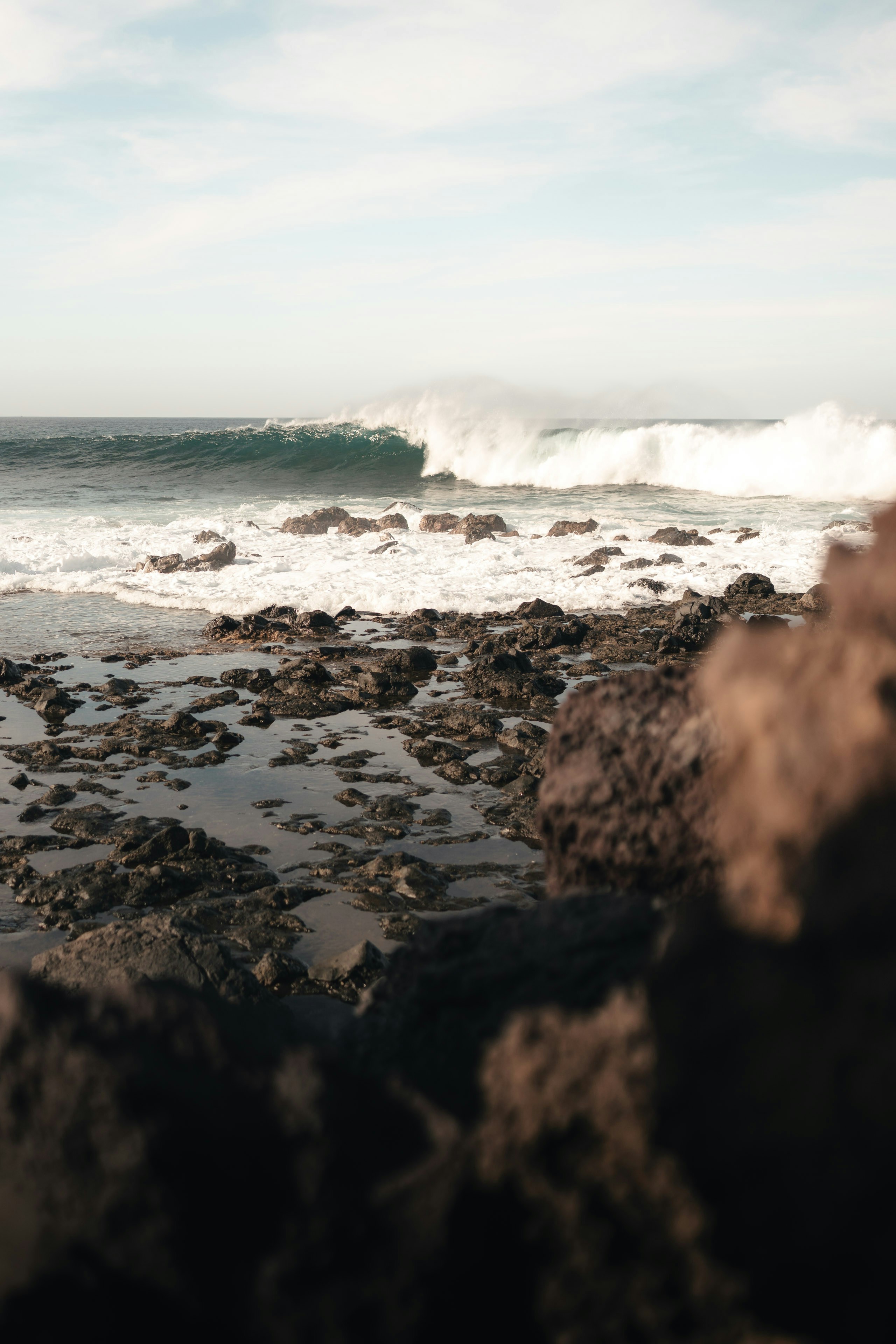 Rugged shoreline pause: A curling Atlantic swell behind jagged lava rocks