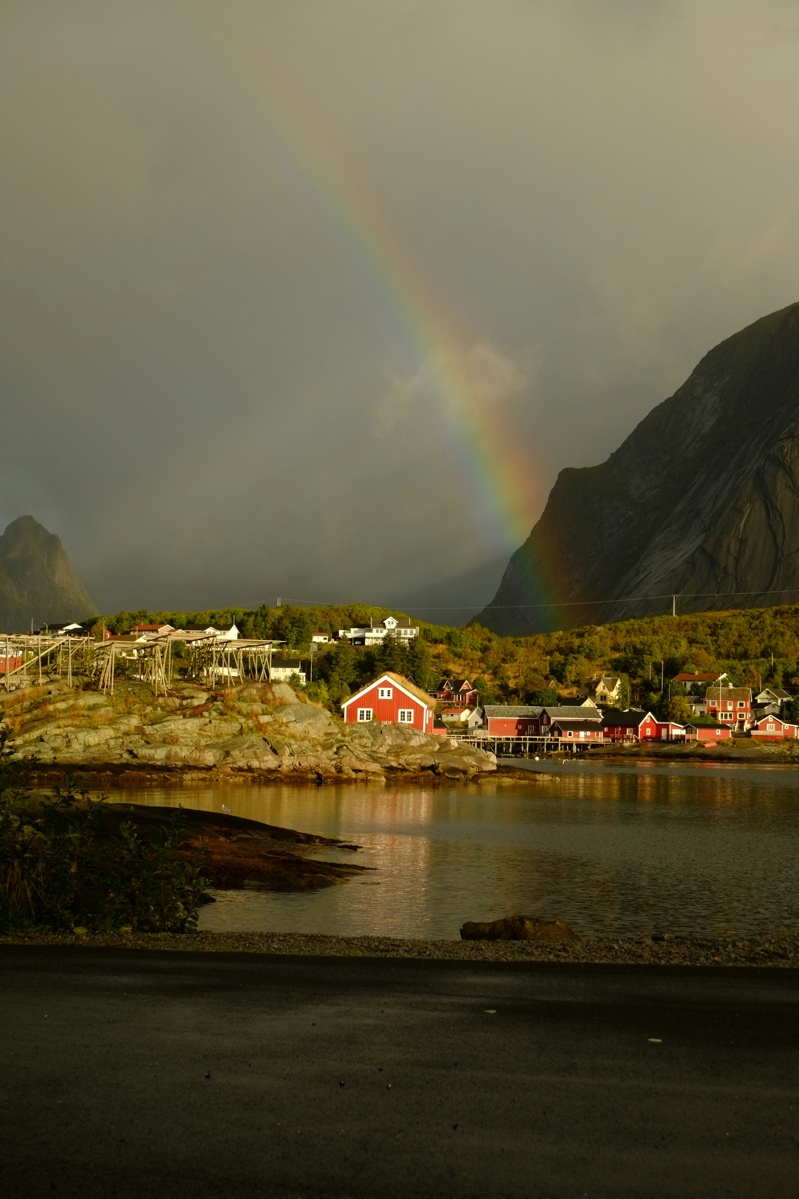 Rainbow over a coastal village tucked at the foot of towering cliffs