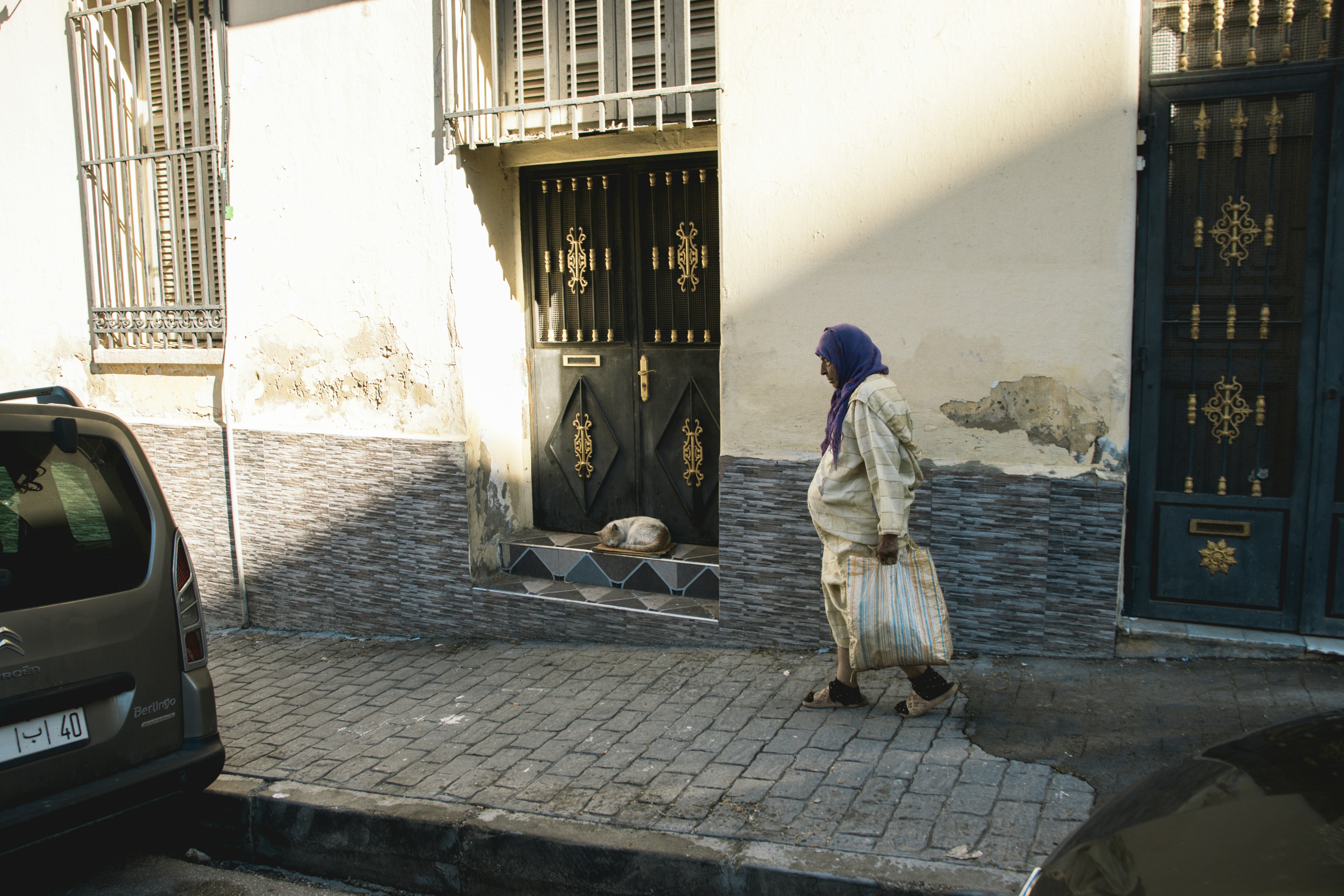Footpath Encounter: A Woman in a Blue Headscarf Passes a Closed Door