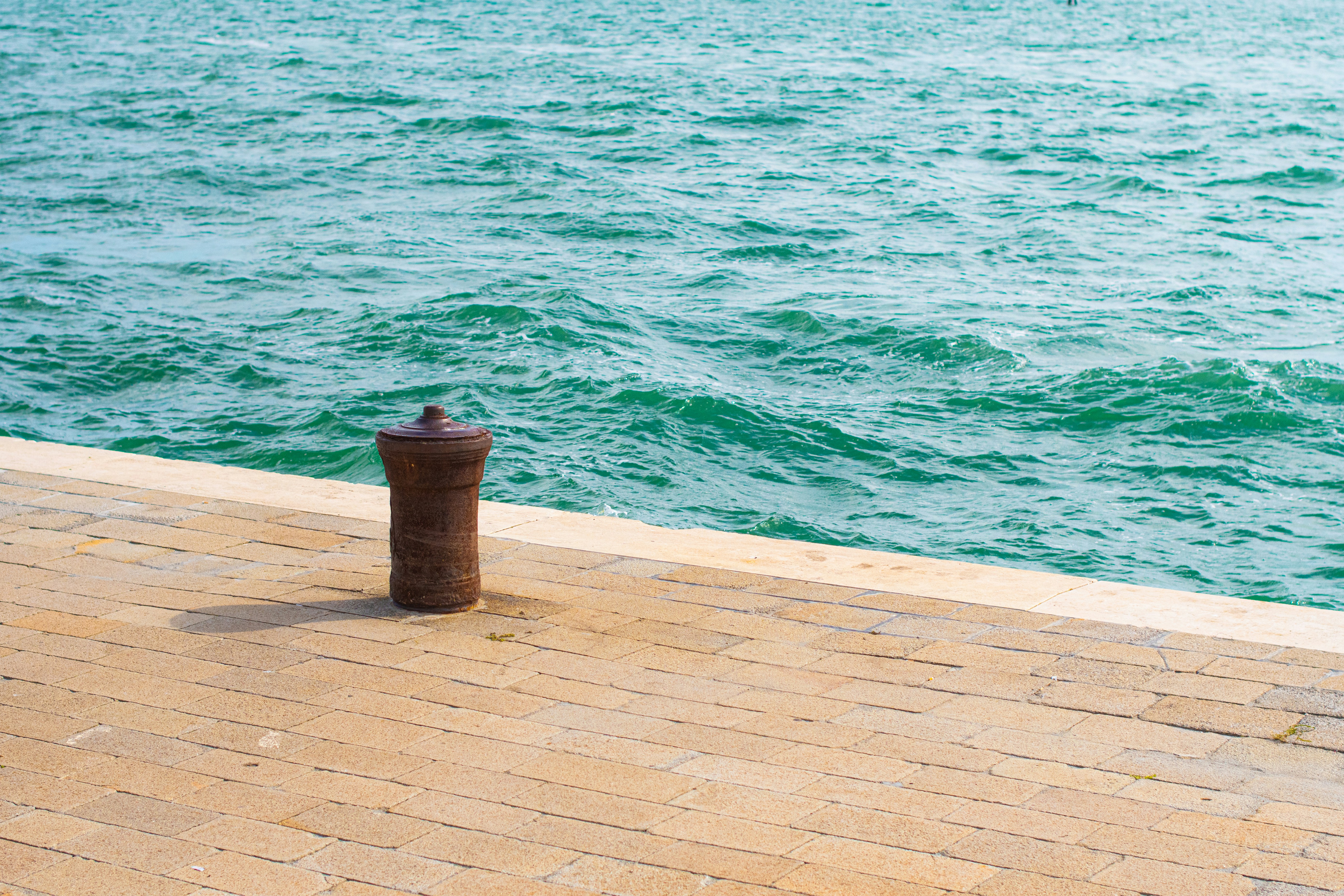Rusted mooring post at the jetty edge meeting turquoise sea