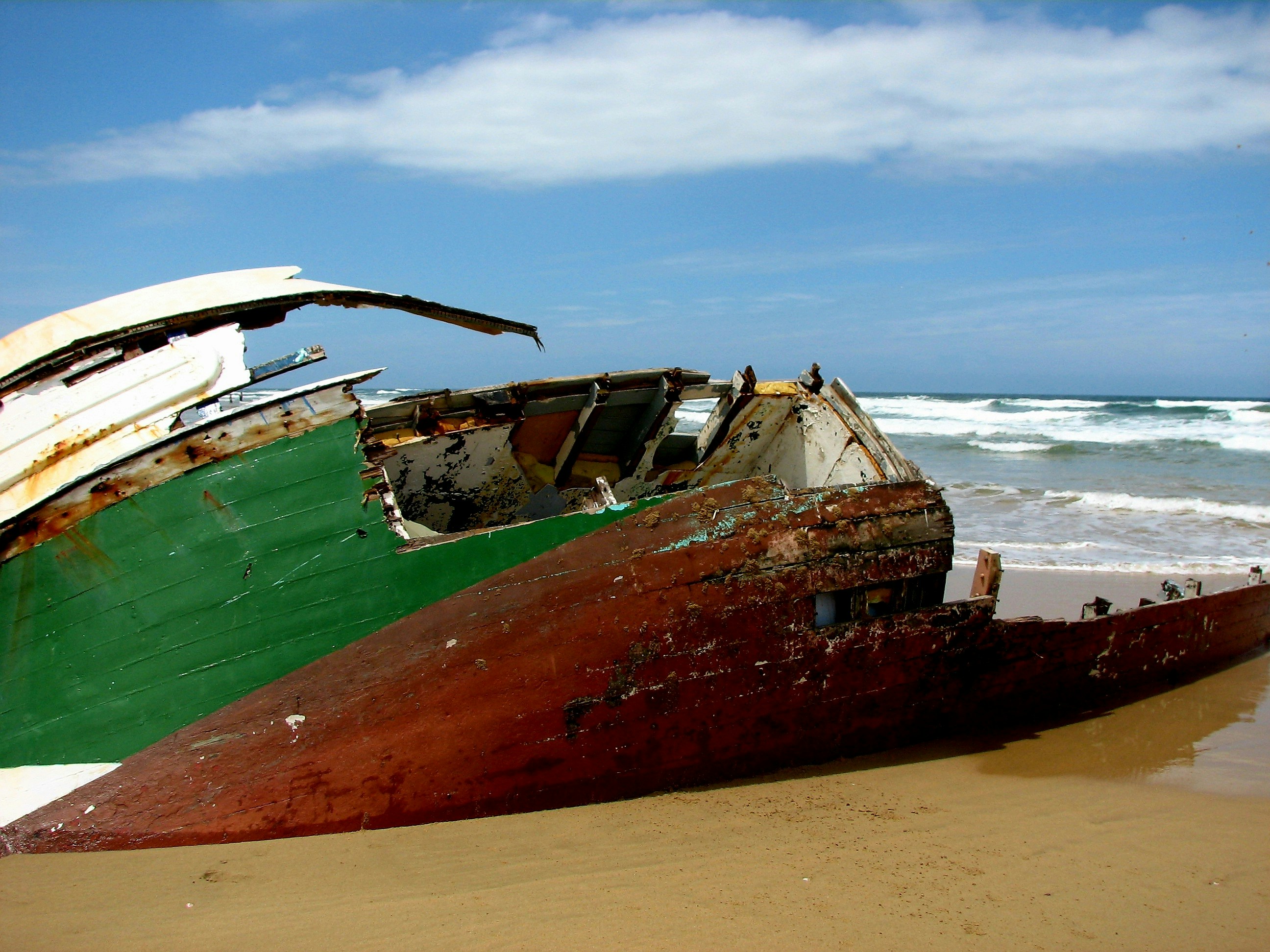 Wrecked boat on a sandy beach with ocean waves