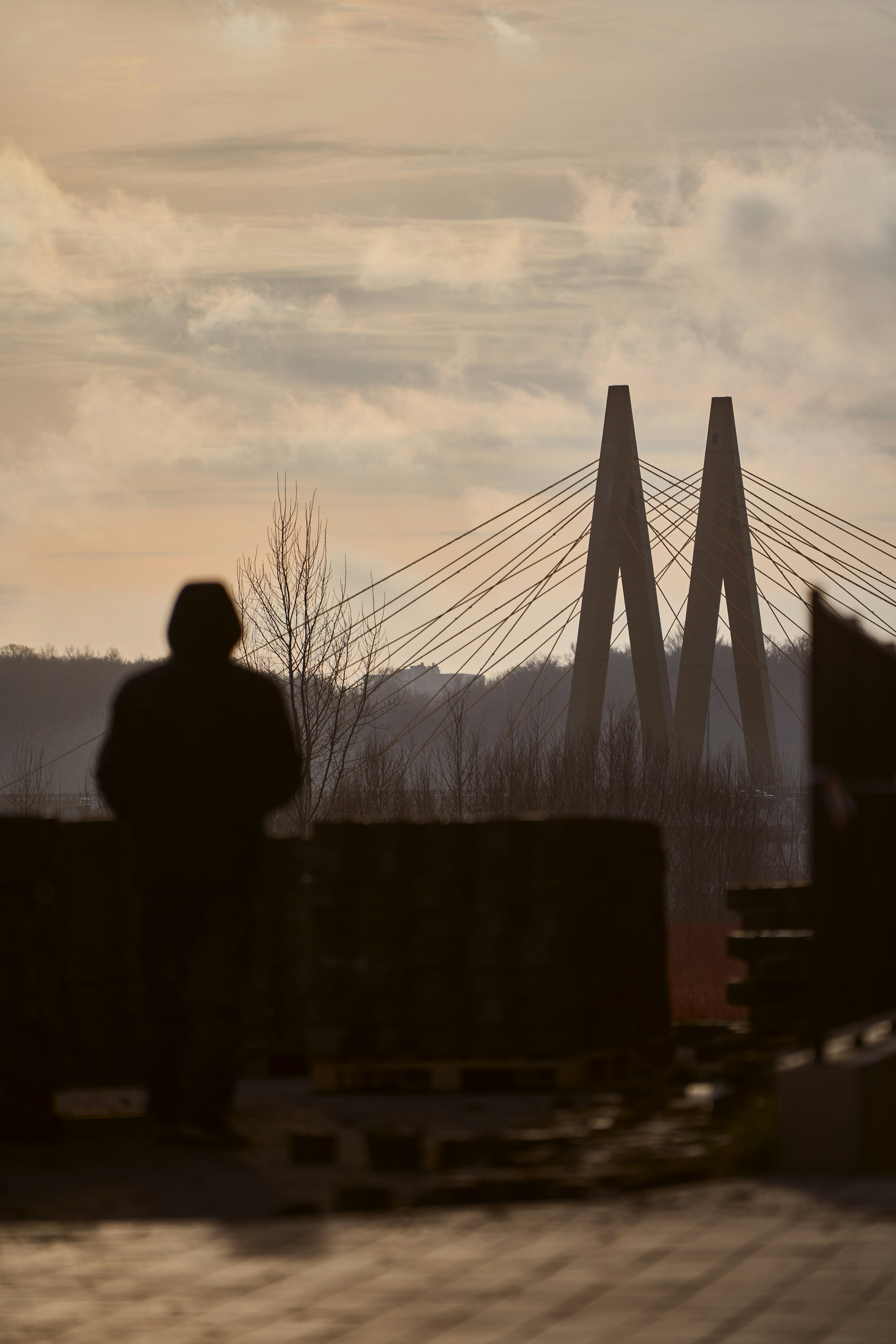 Silhouette at Dusk: A Bridge Tower Framed by Workers and Shadows