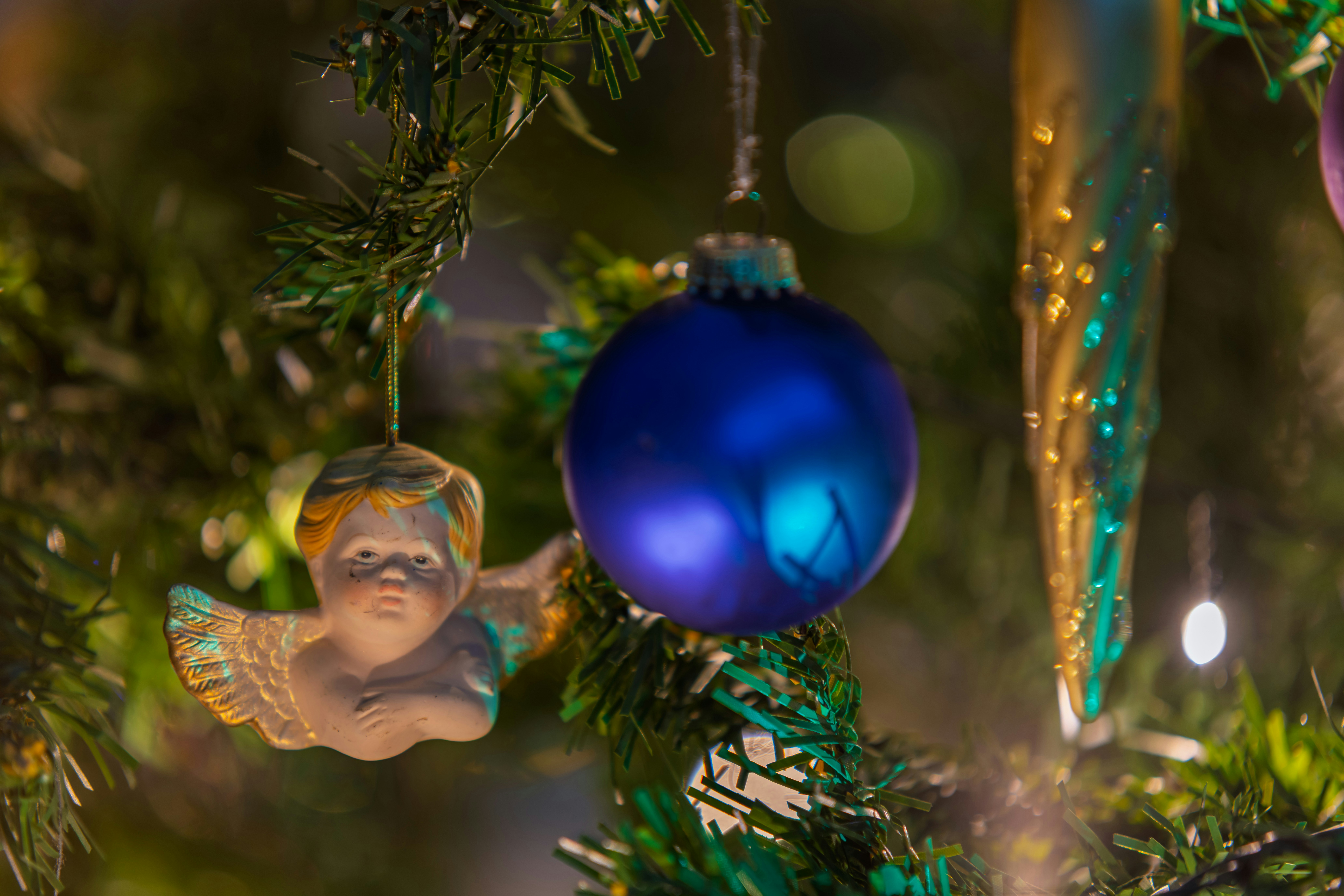 Angel Ornament and Blue Bauble Quietly Glow on a Festive Evergreen