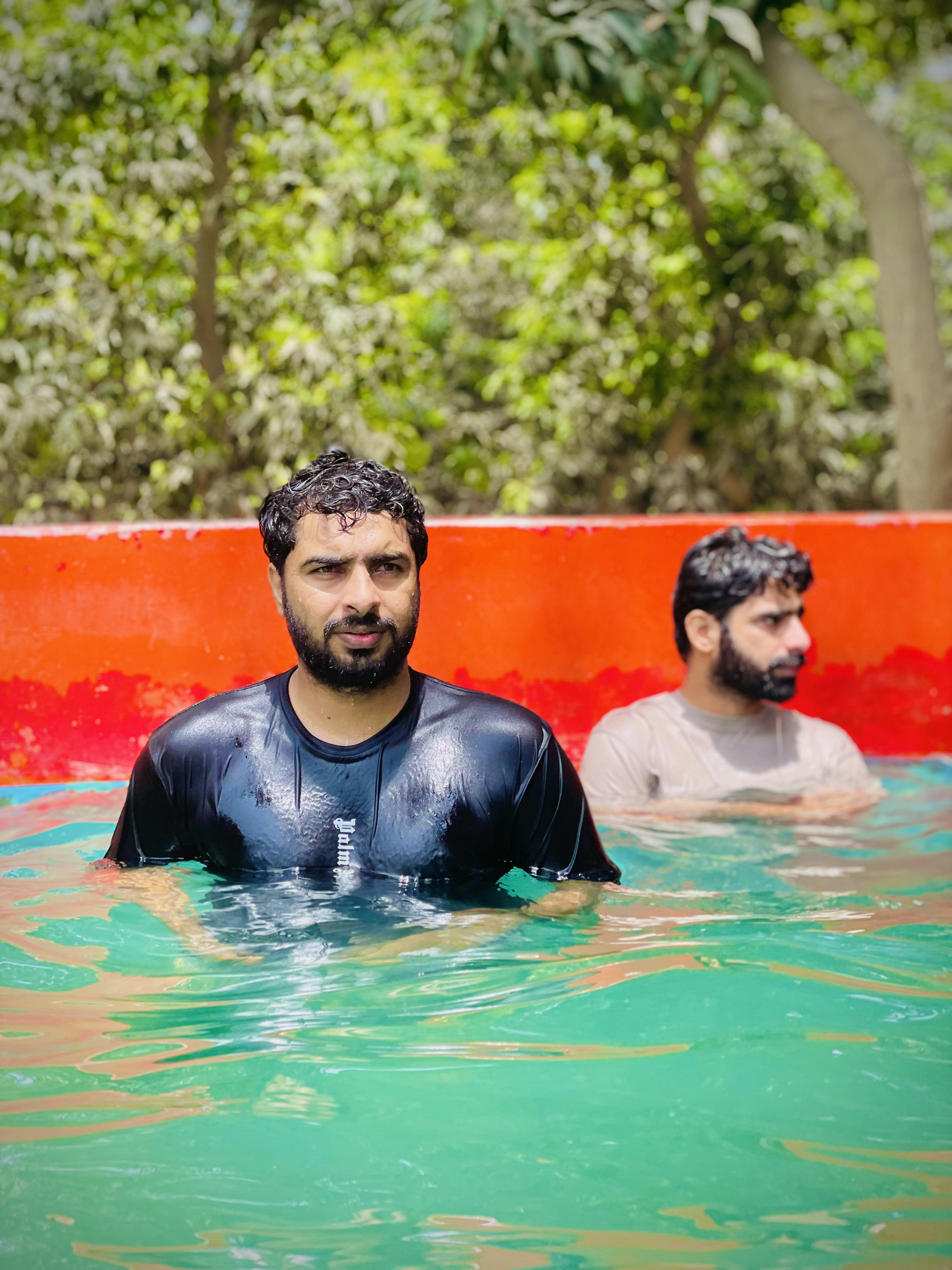 Two Figures in a Sunlit Pool: A Quiet Moment by the Red Barrier