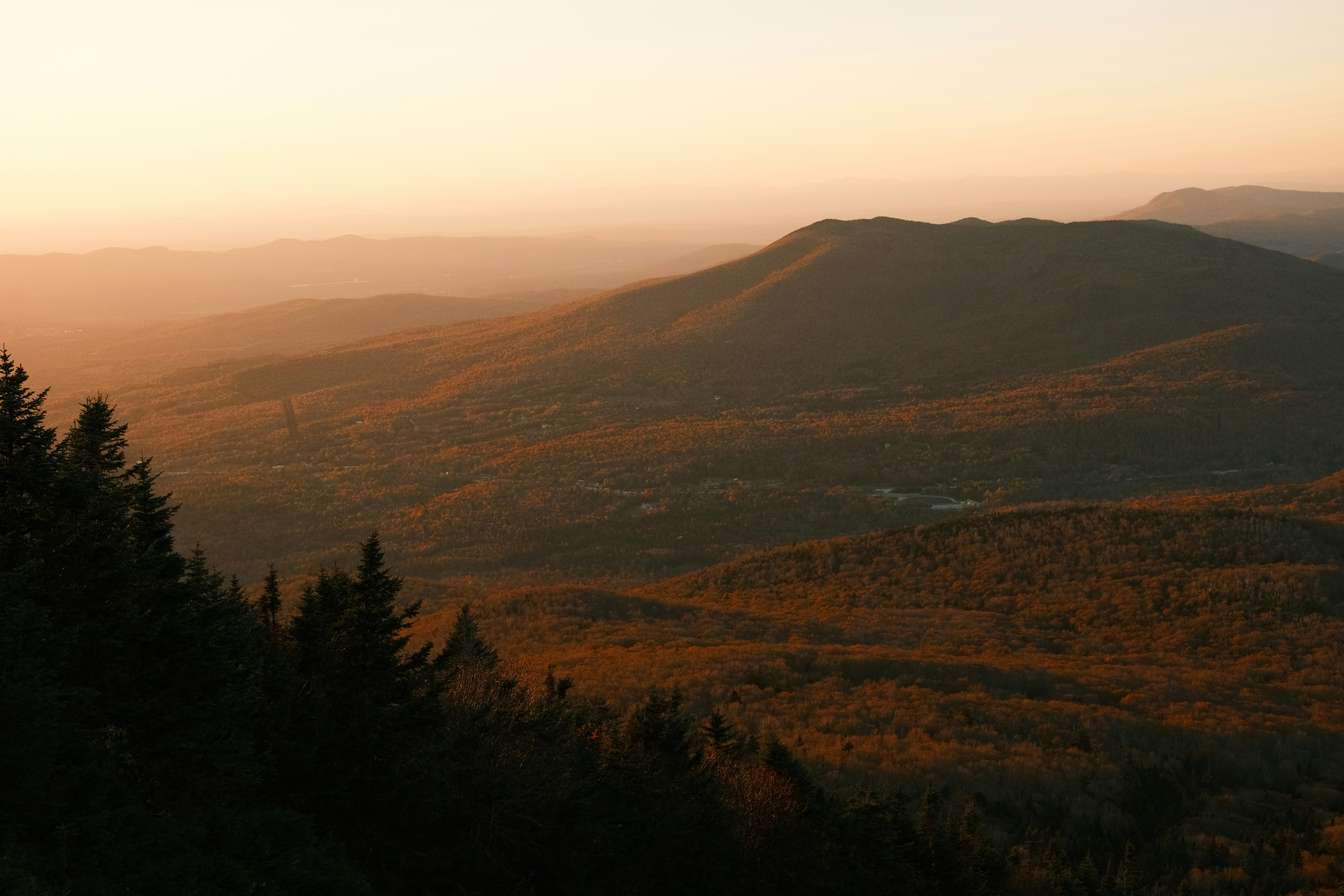 Golden hour mountain landscape with warm autumn tones and soft atmospheric layers