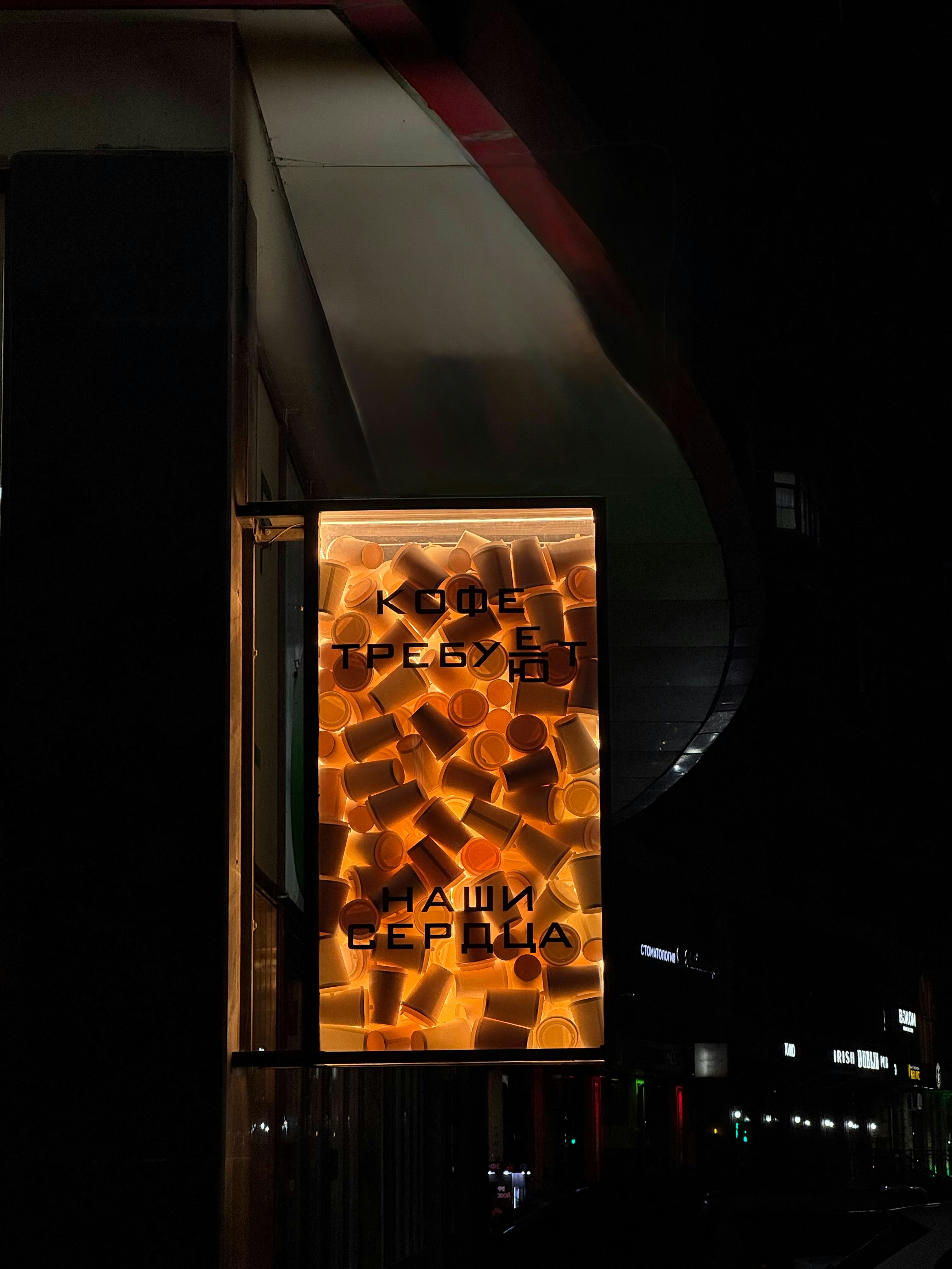 Glowing sign of orange capsules in a dark urban storefront