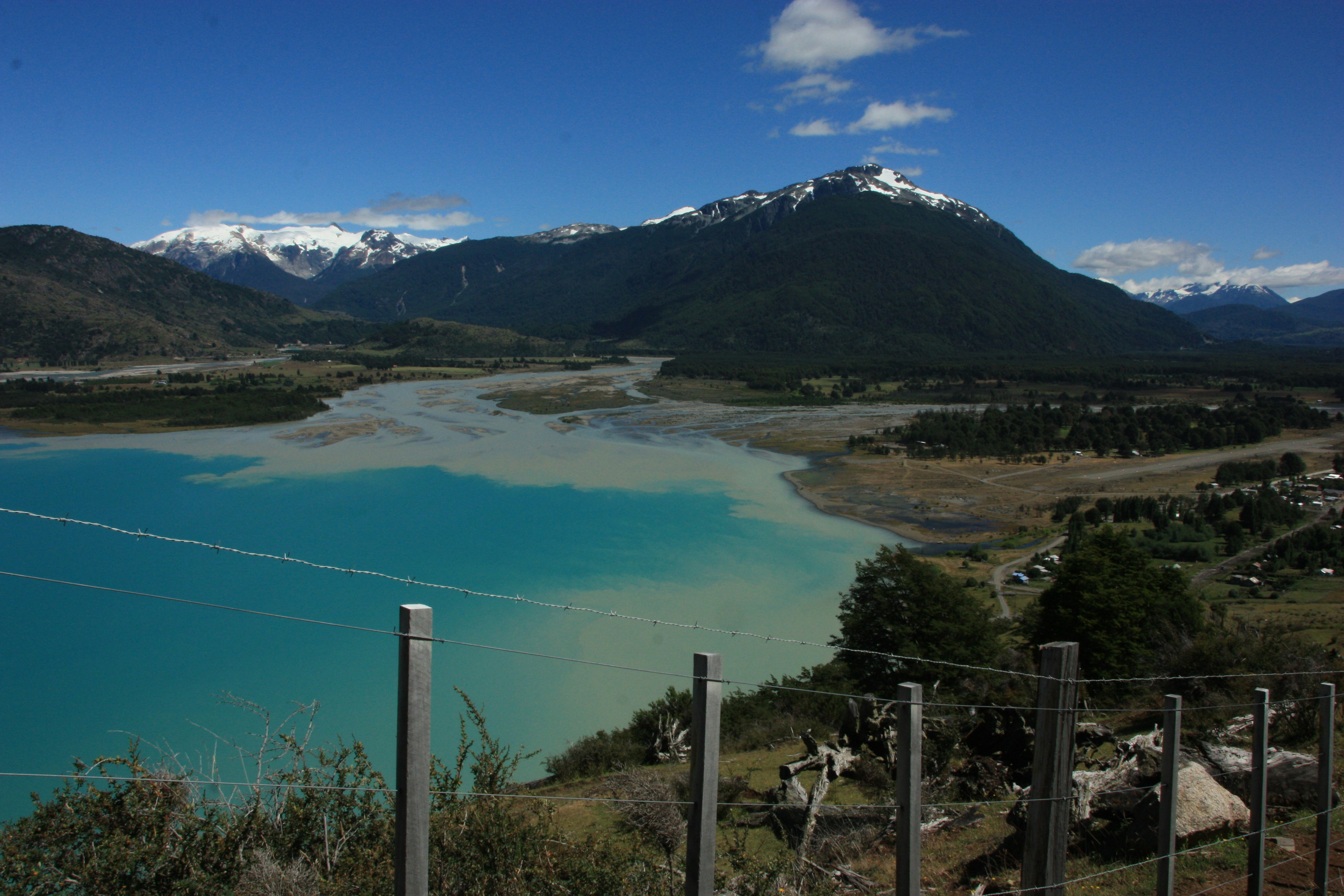 Turquoise Lake Serene: A Fence-Line View toward Snow-Capped Peaks
