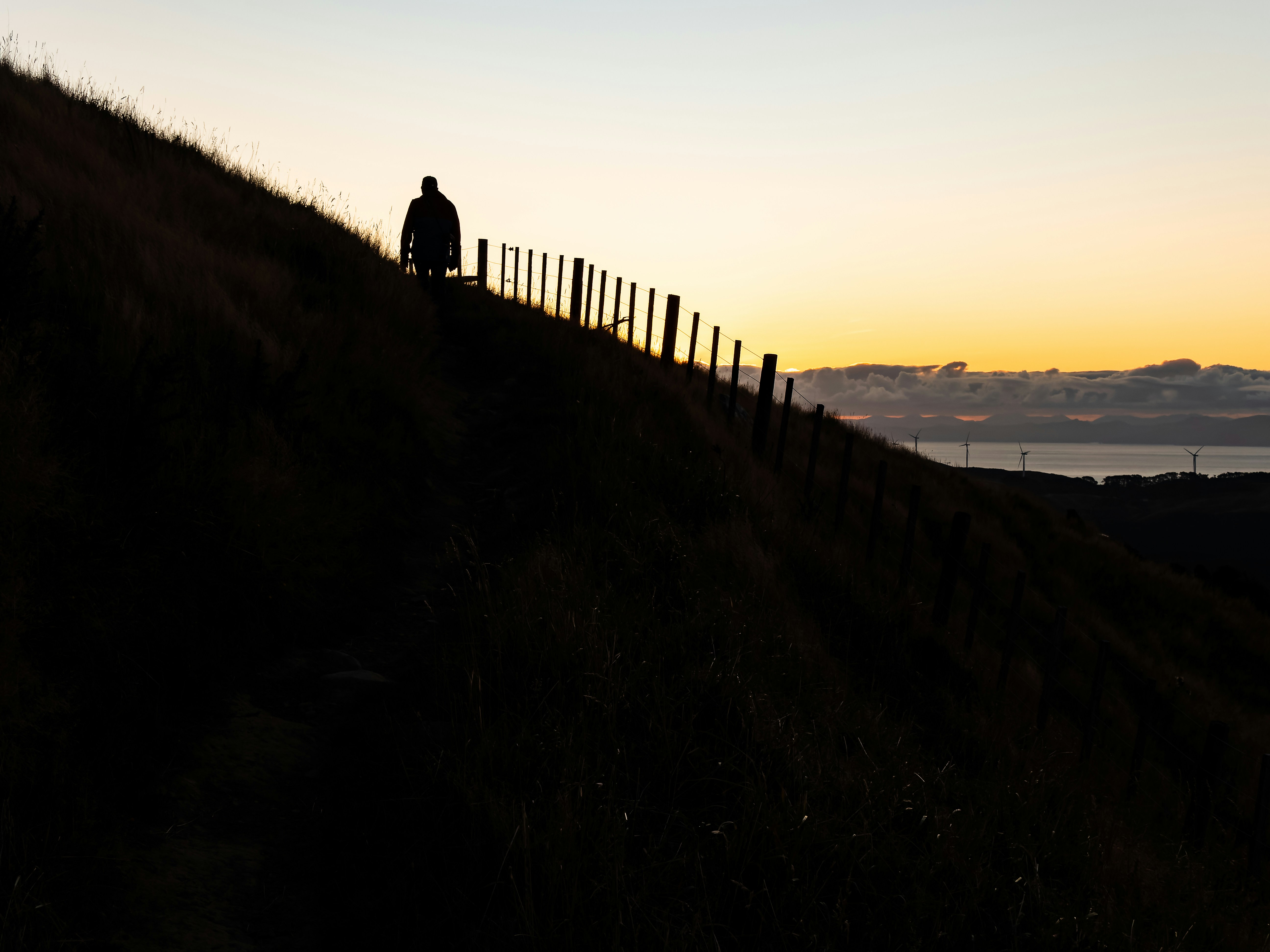 Silhouette on the Cliff: A Hushed Walk at Sunset