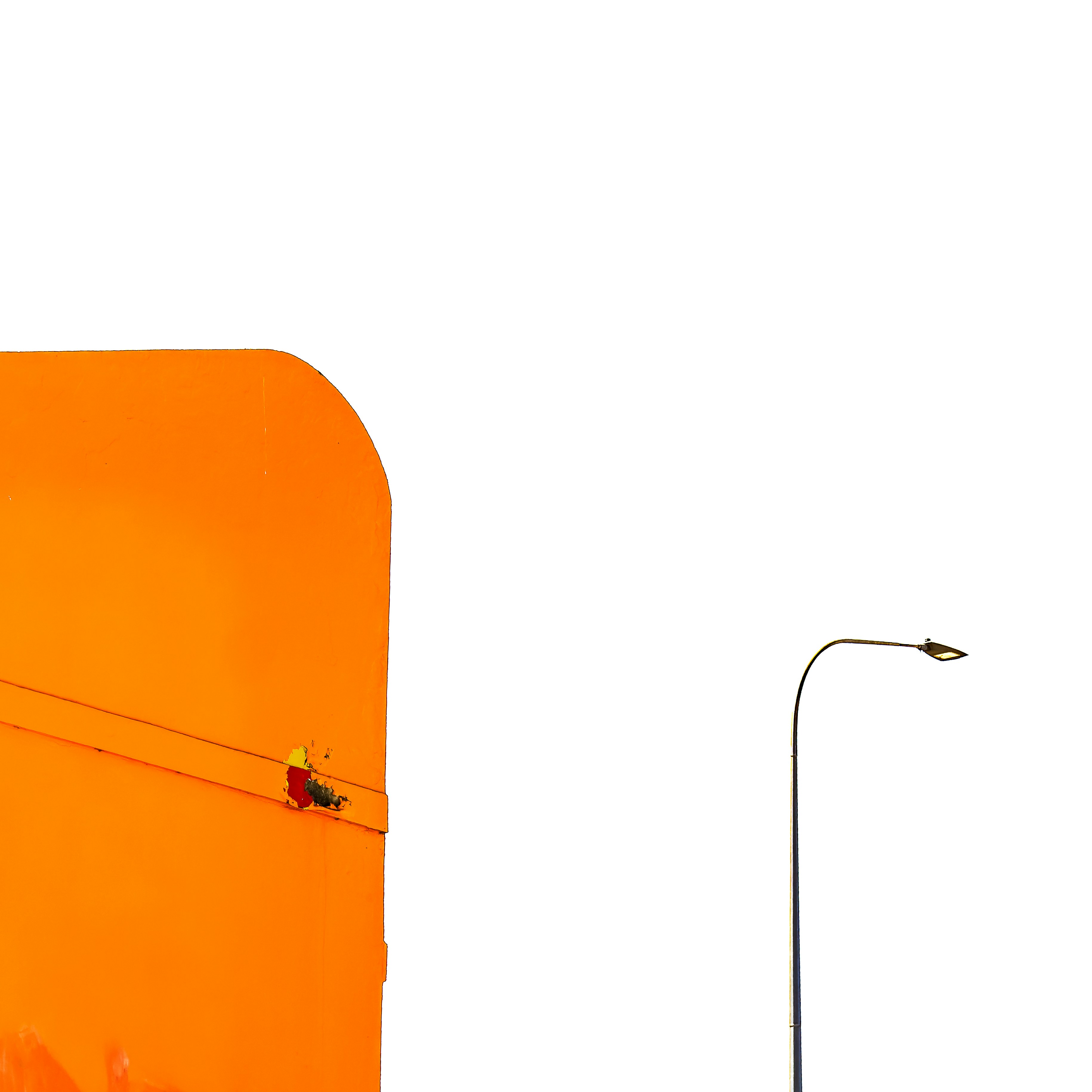 the orange facade of a warehouse with a street lamp