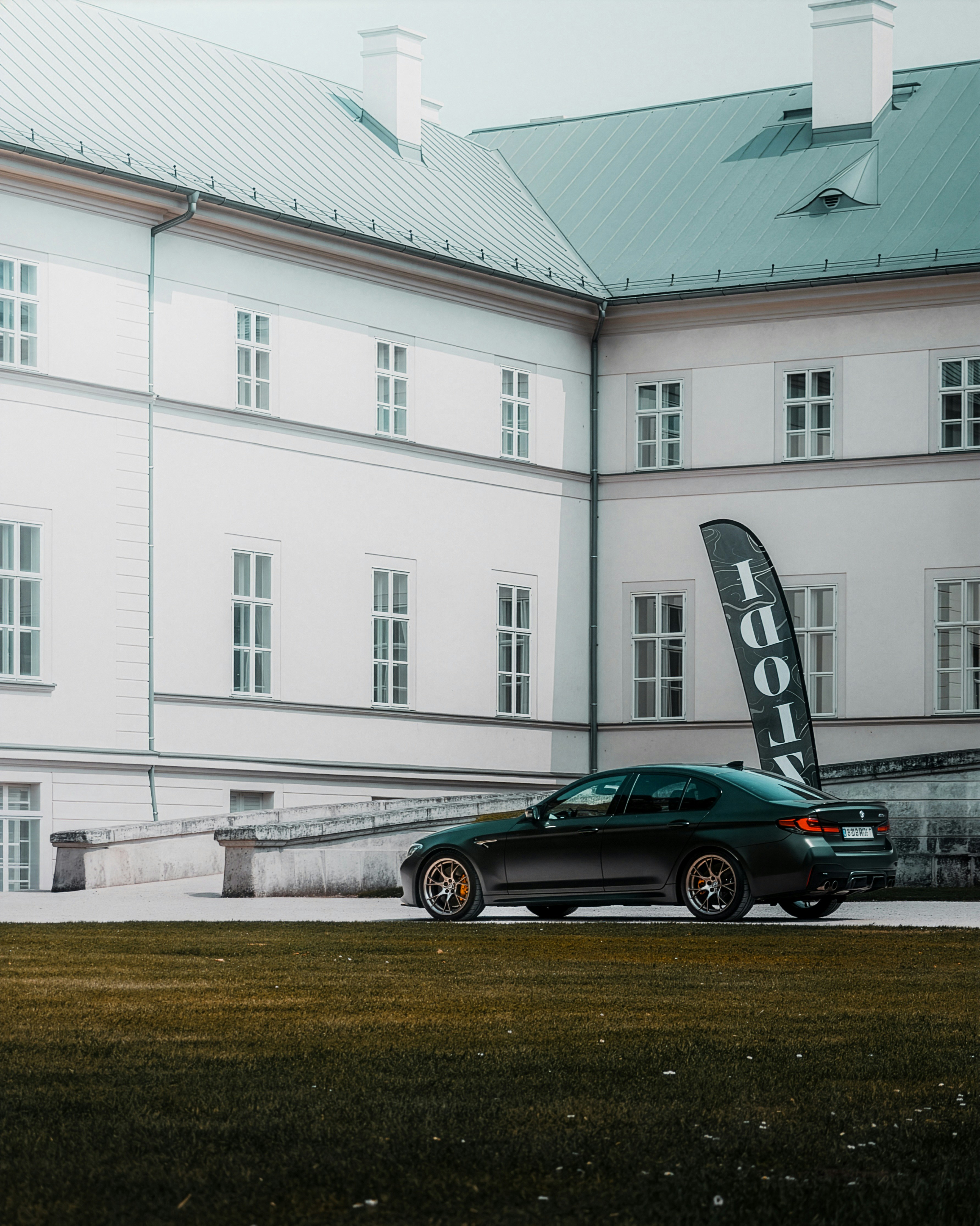 Black sedan by a stately manor courtyard
