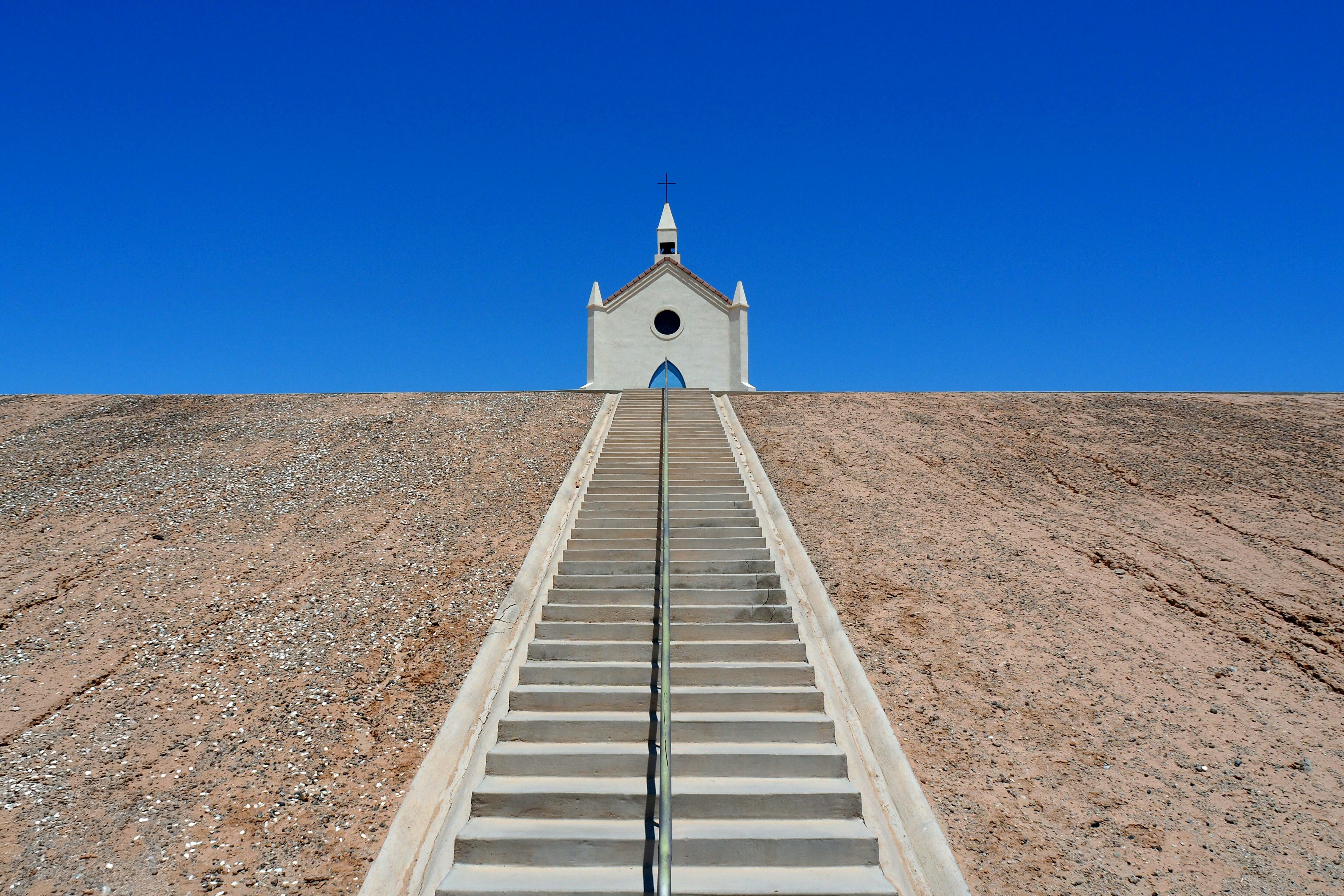 Ascend to the White Chapel: Stairs Framing a Clear Blue Ascent