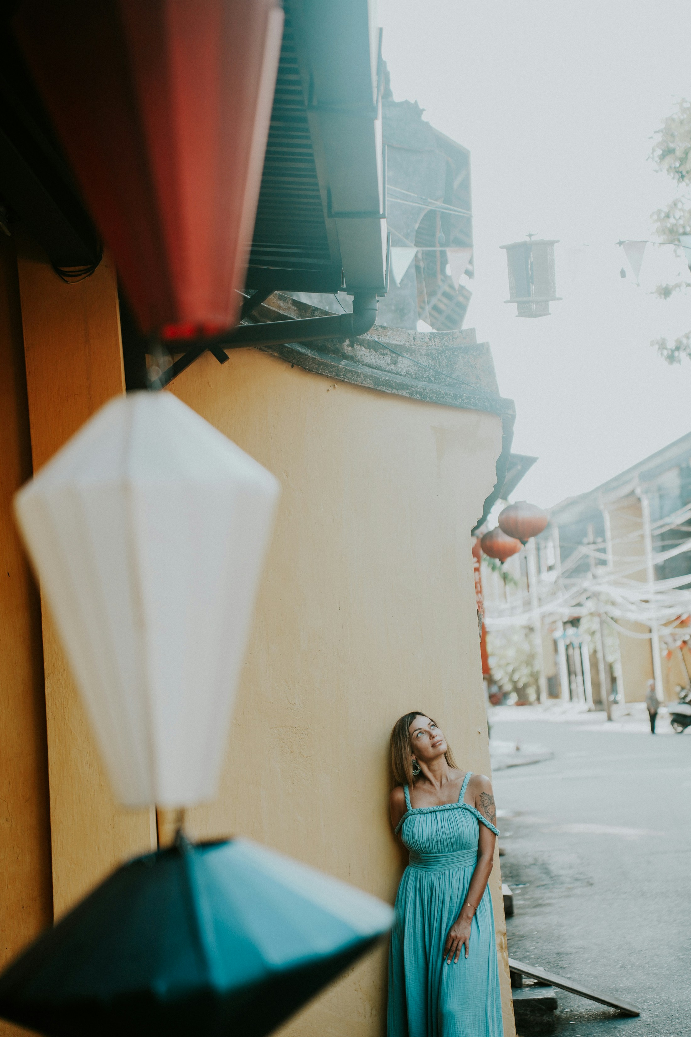 Turquoise dress in a sunlit alleyway by a yellow wall