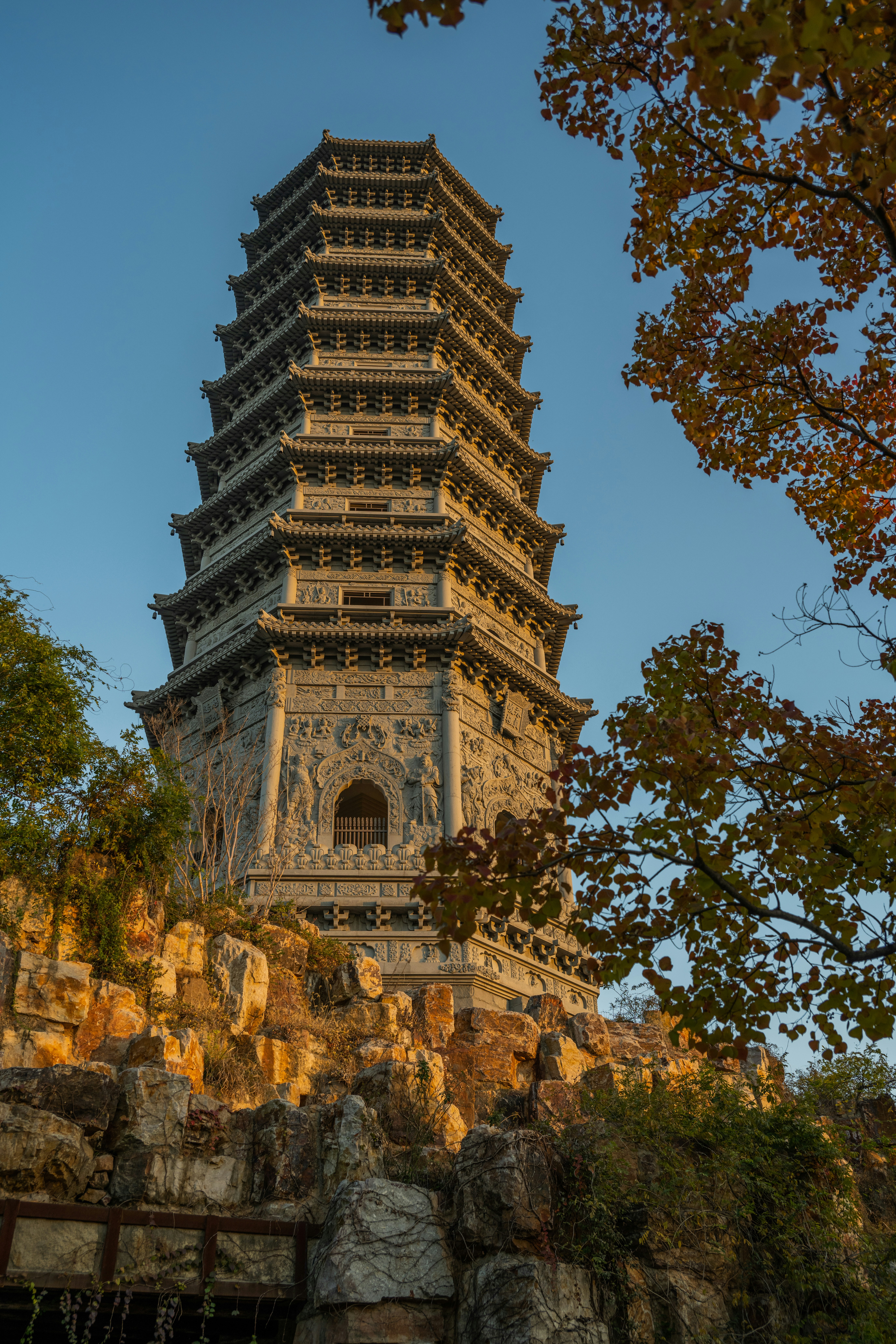 Stone Pagoda rising above sunlit ruins and autumn foliage