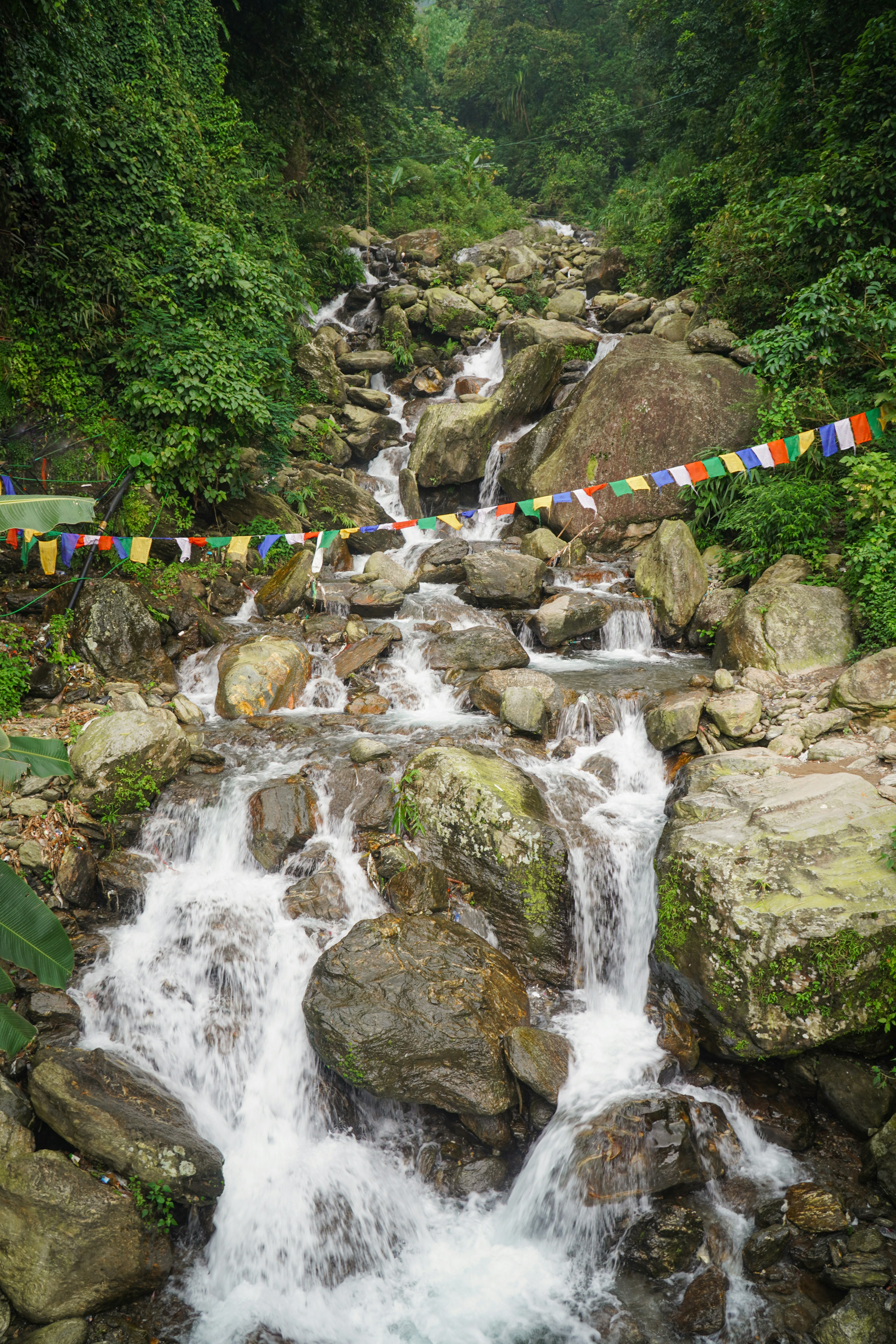 Prismatic Cascade: Prayer Flags Amid Mountain Waters