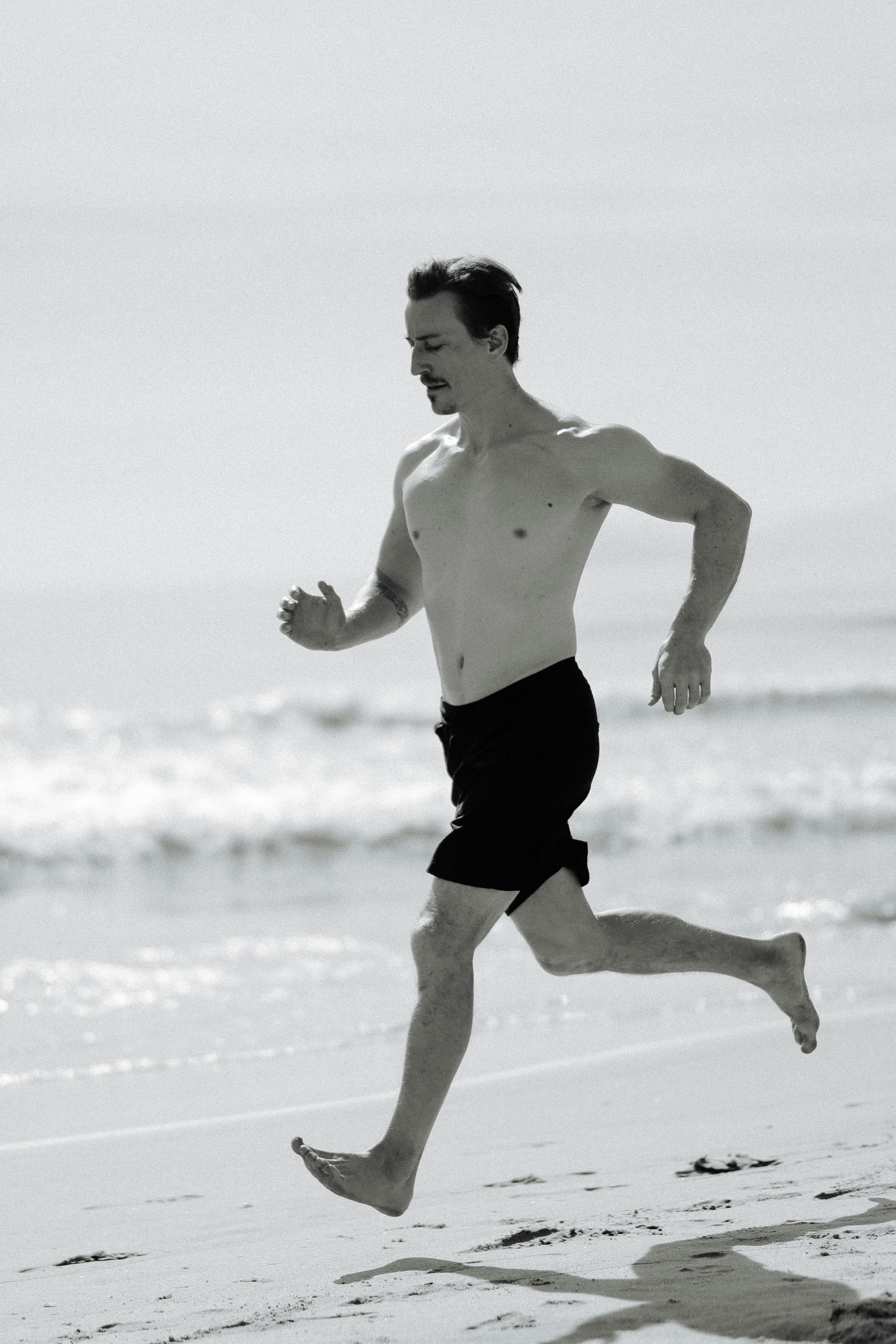 Mid-stride on the Shore: A Man Runs Along the Beach
