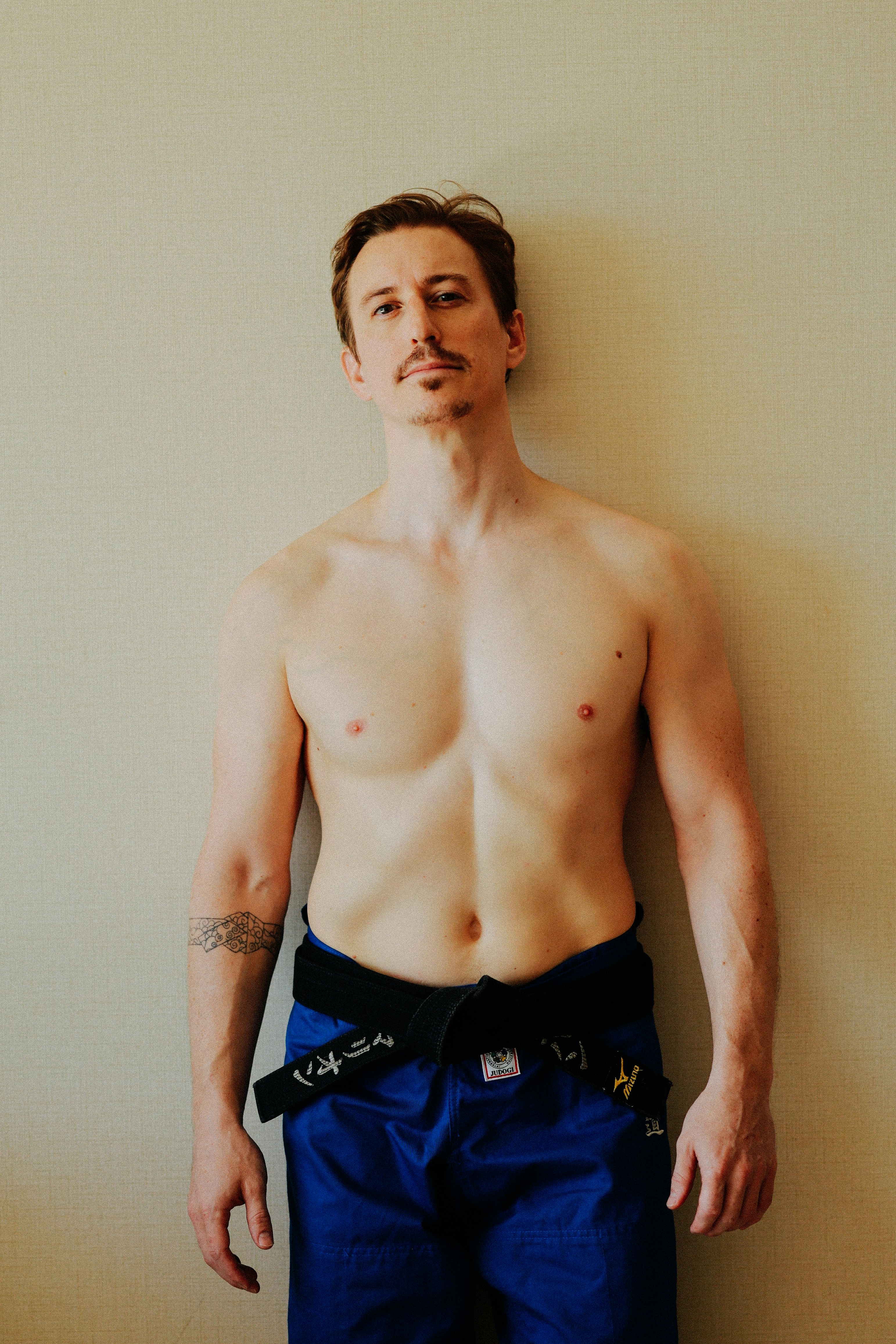 Centered Confidence: A Shirtless Portrait Against a Subtle Hue