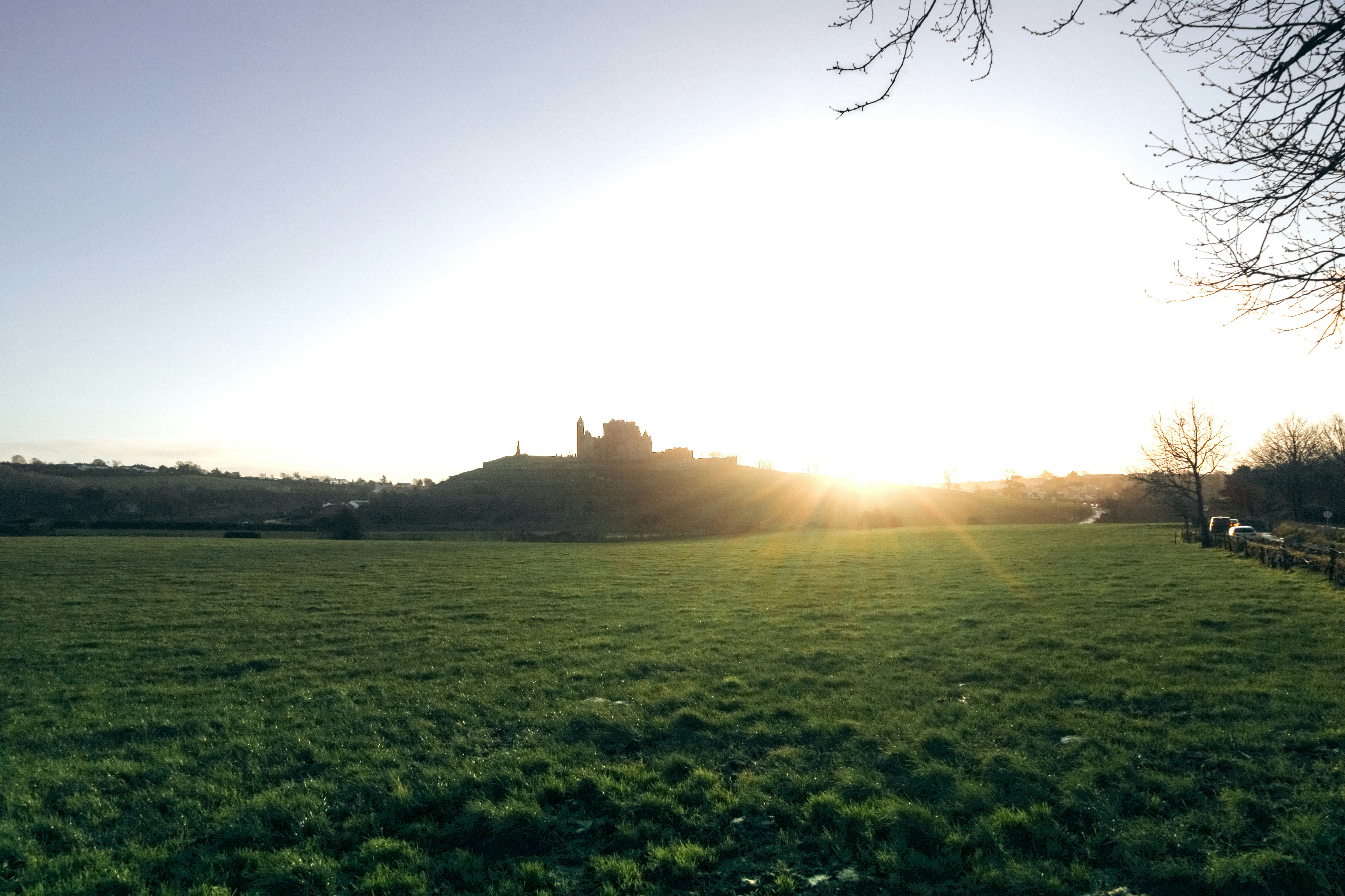 Sunrise Over Open Field with Distant Castle Silhouette