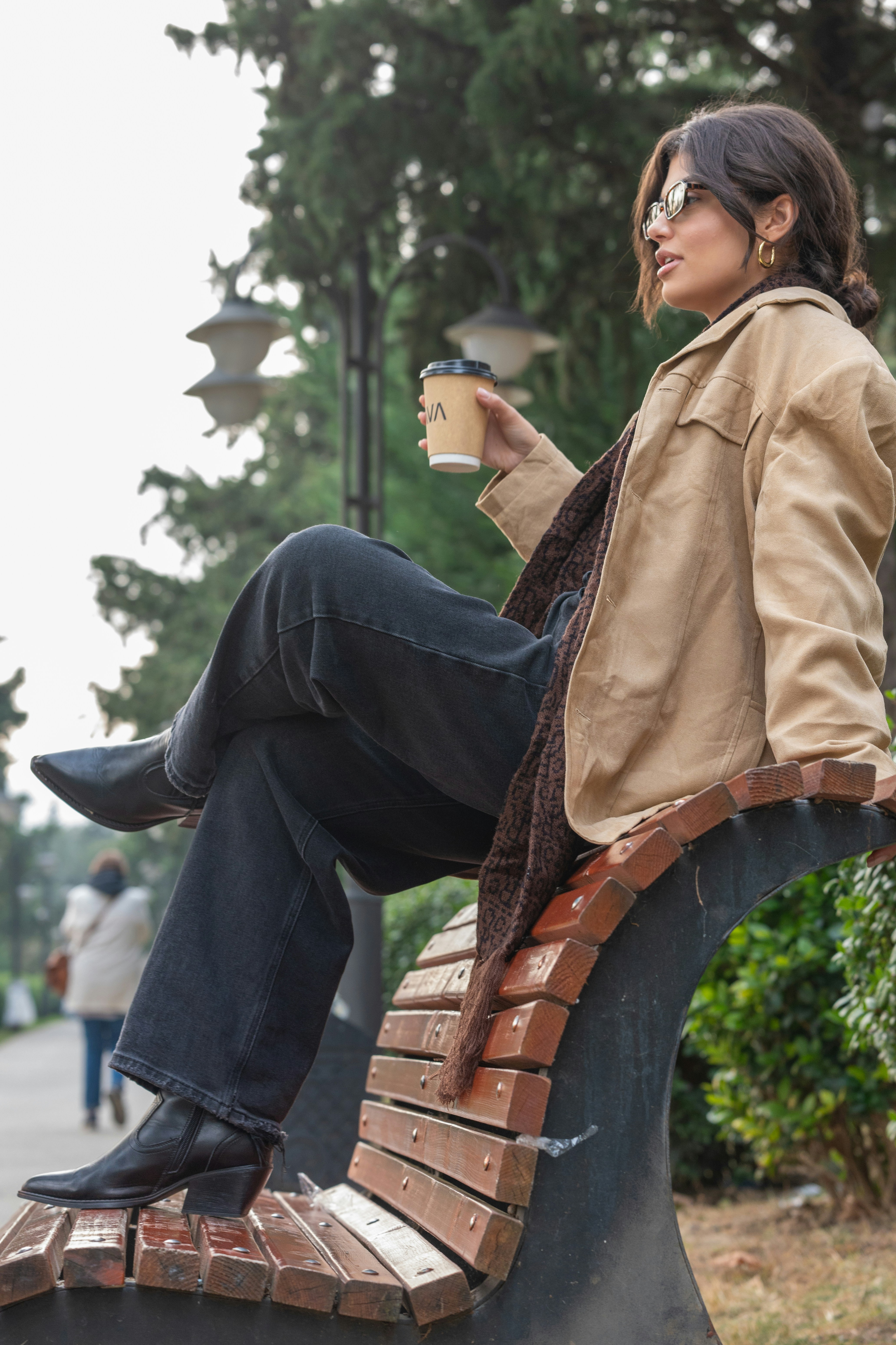 Cafe Vista: A woman reclines on a curved park bench with a coffee cup