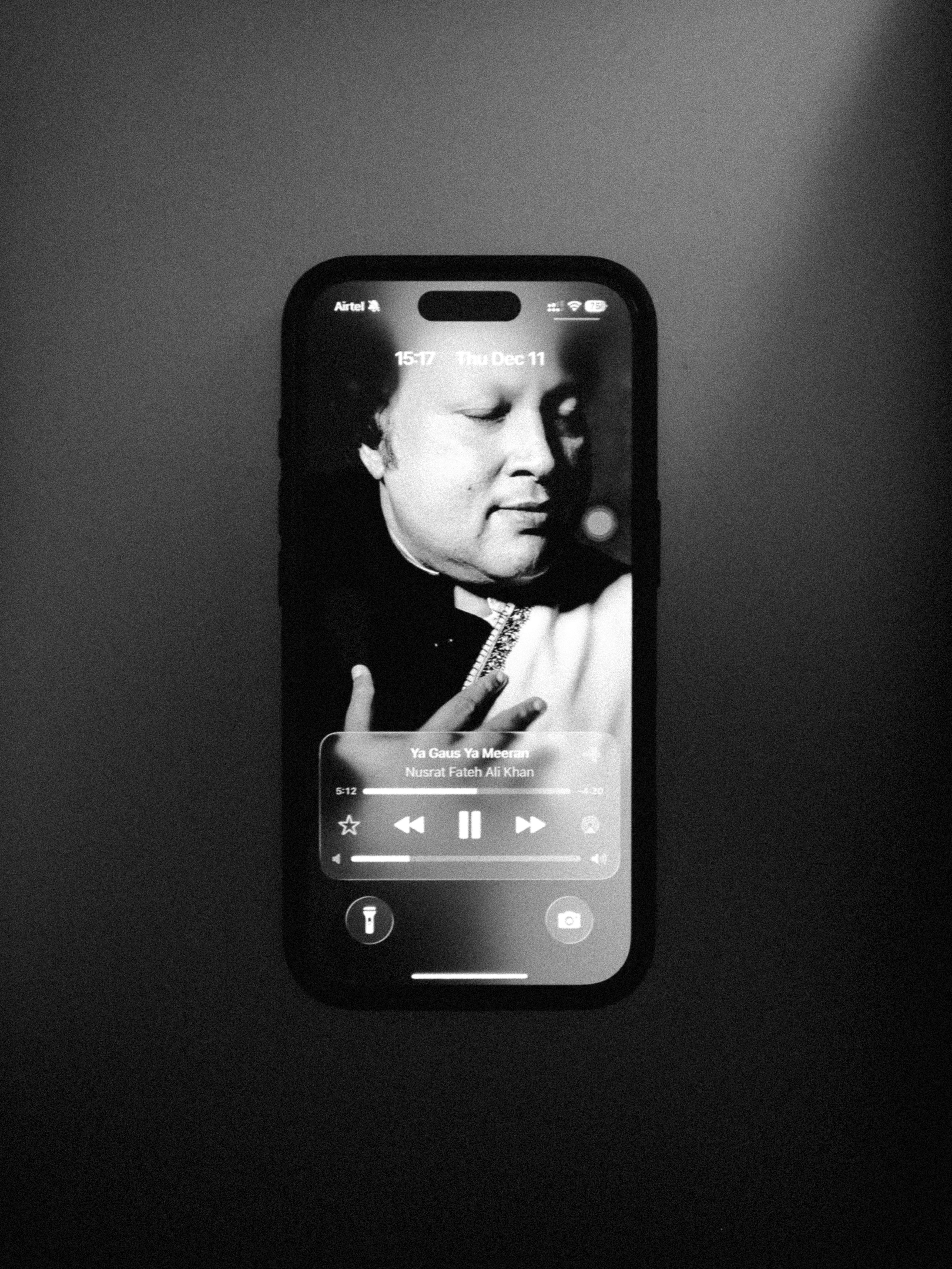 Man's face on a smartphone screen with music player.