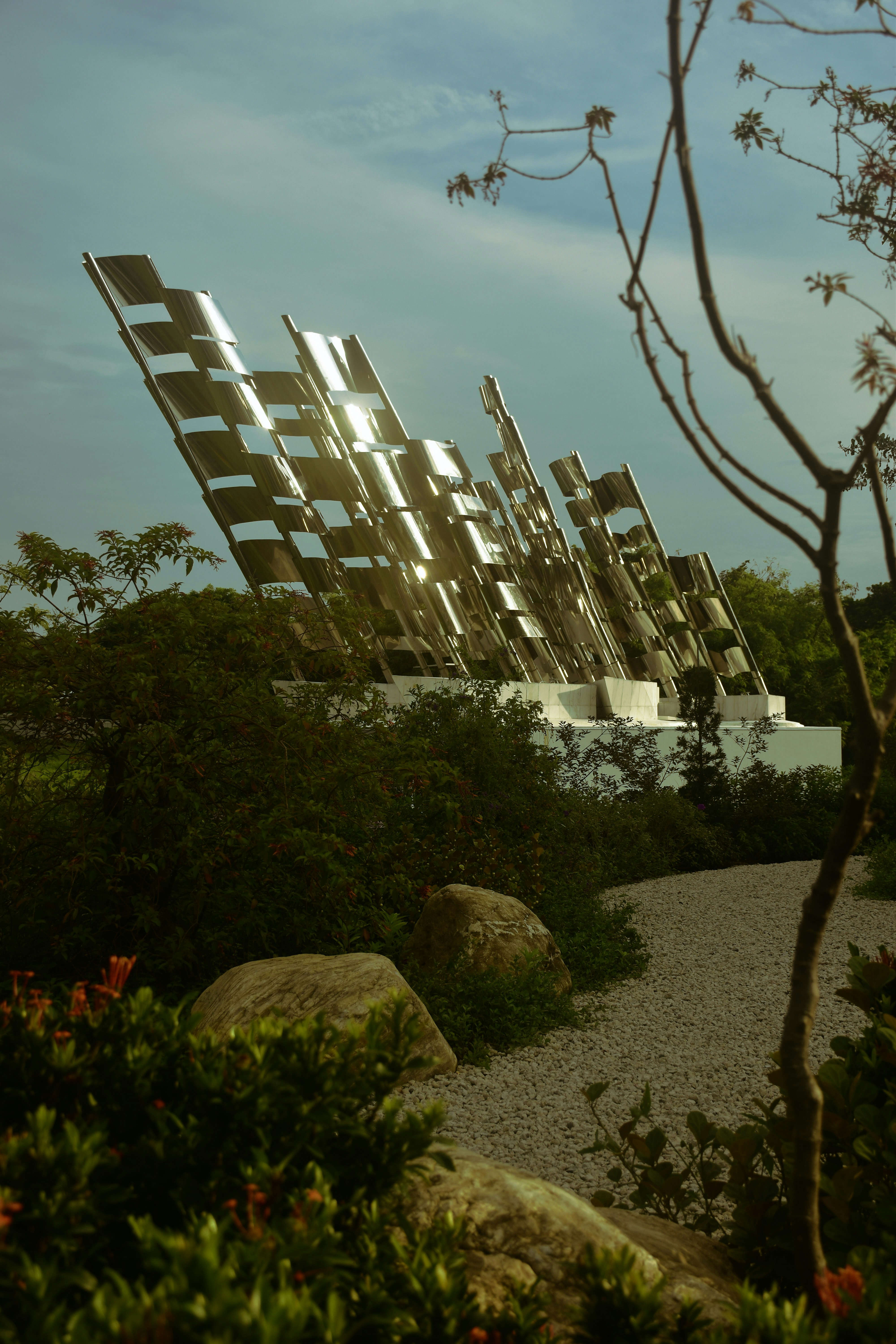 Reflective metallic sculptures rising above the gravel garden