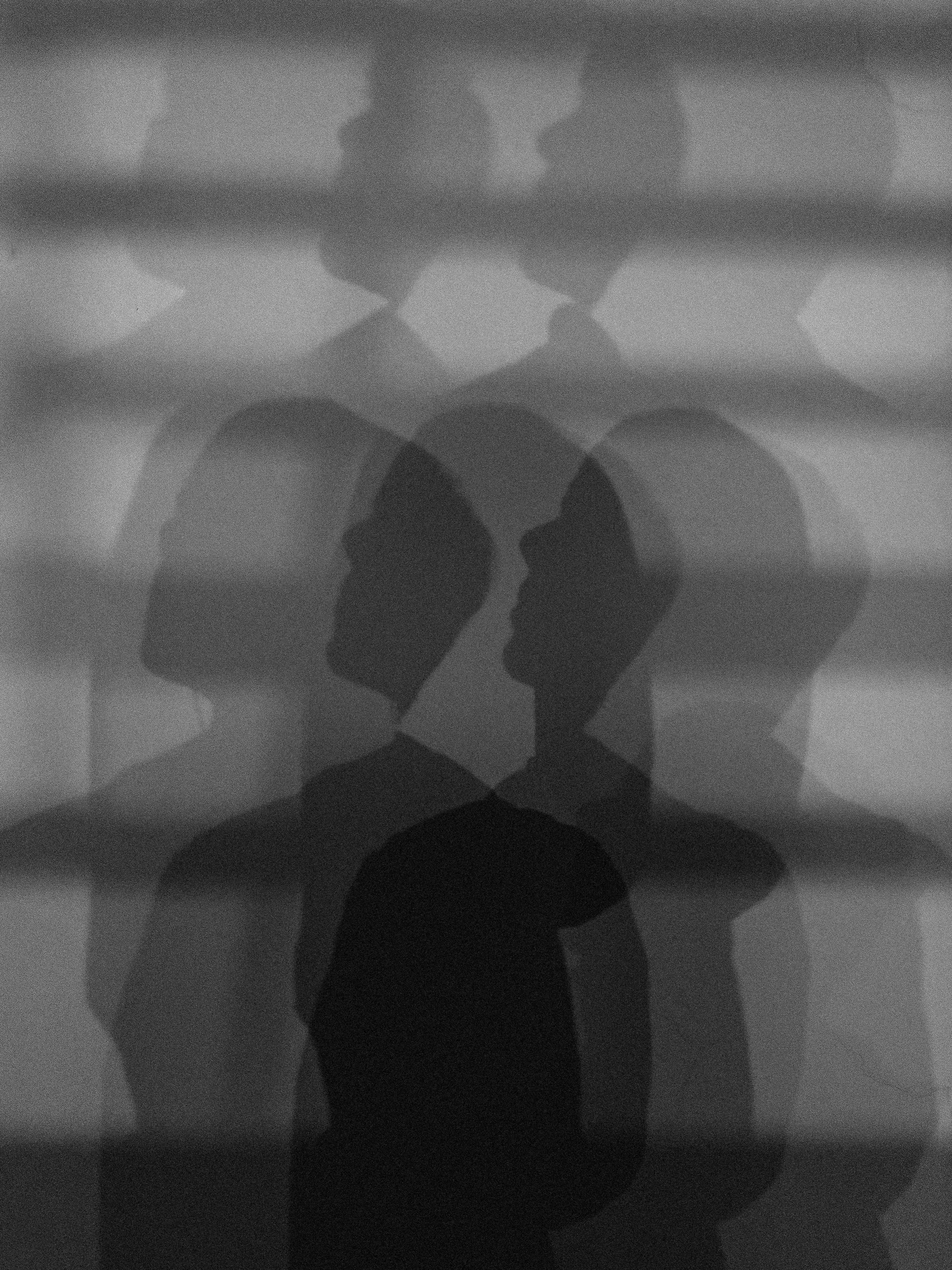 Multiple overlapping silhouettes of a person's head and shoulders.
