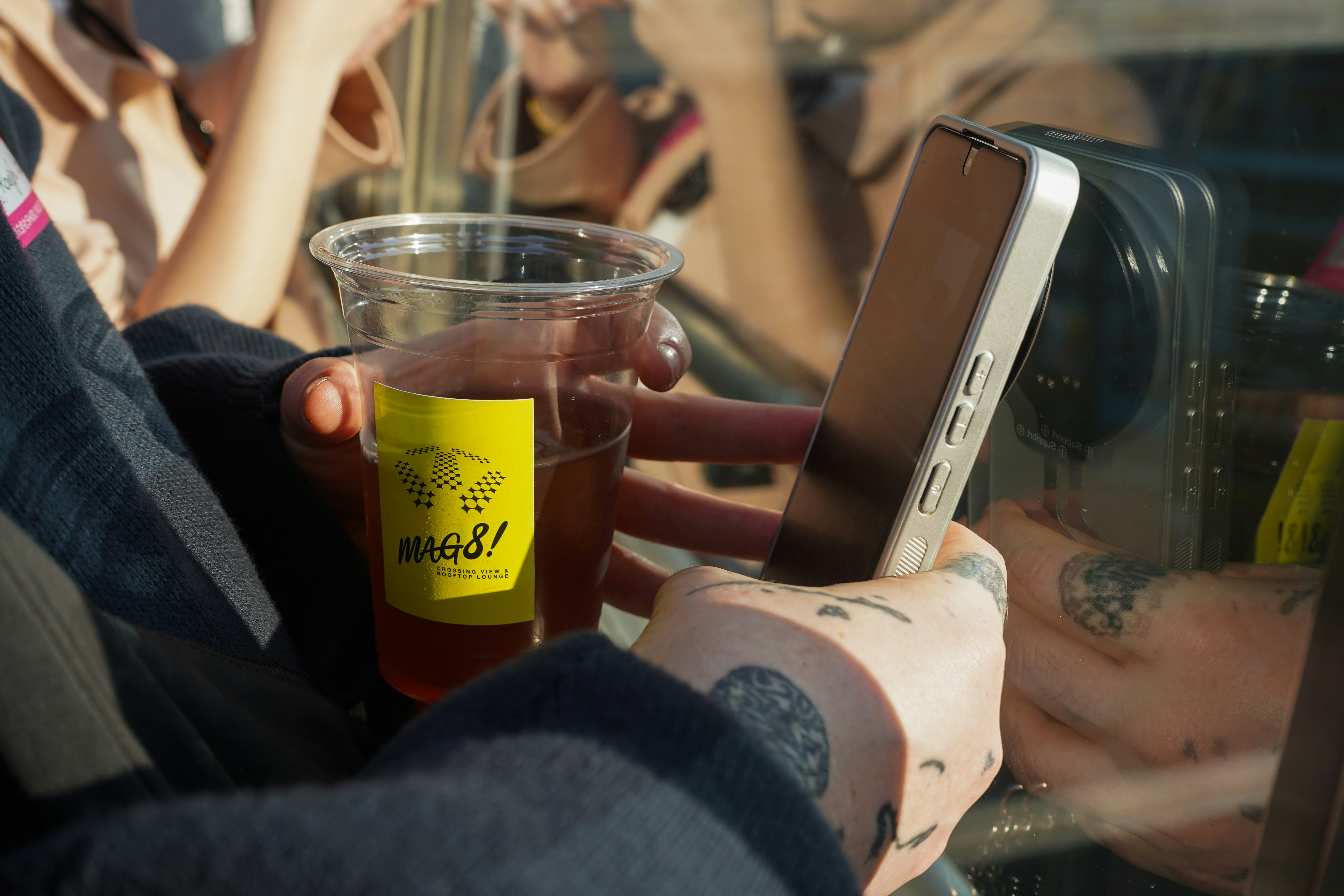 Phone in Hand: a close-up on the drink and device in a bustling cafe window