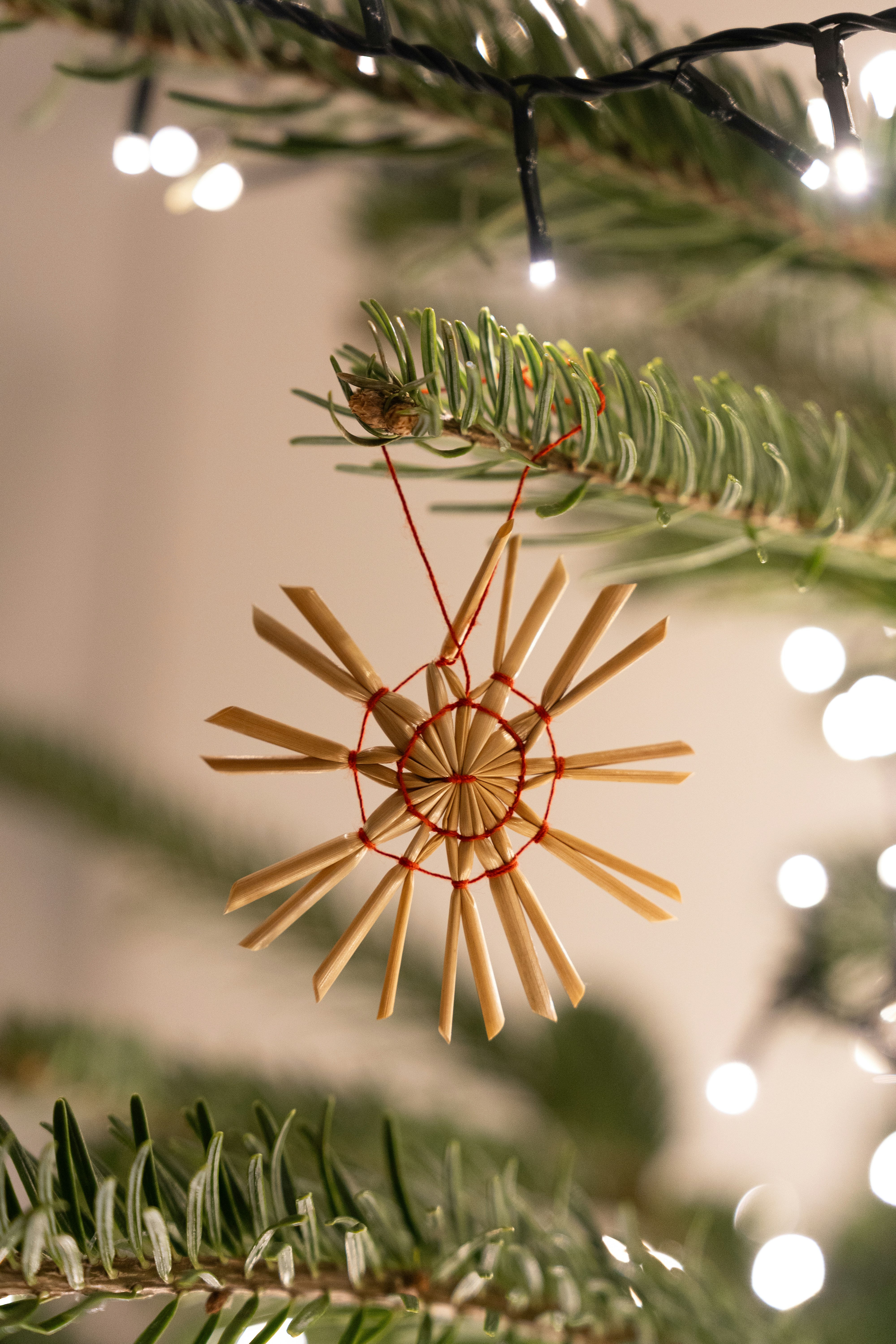 Hanging straw star ornament on a softly lit Christmas tree