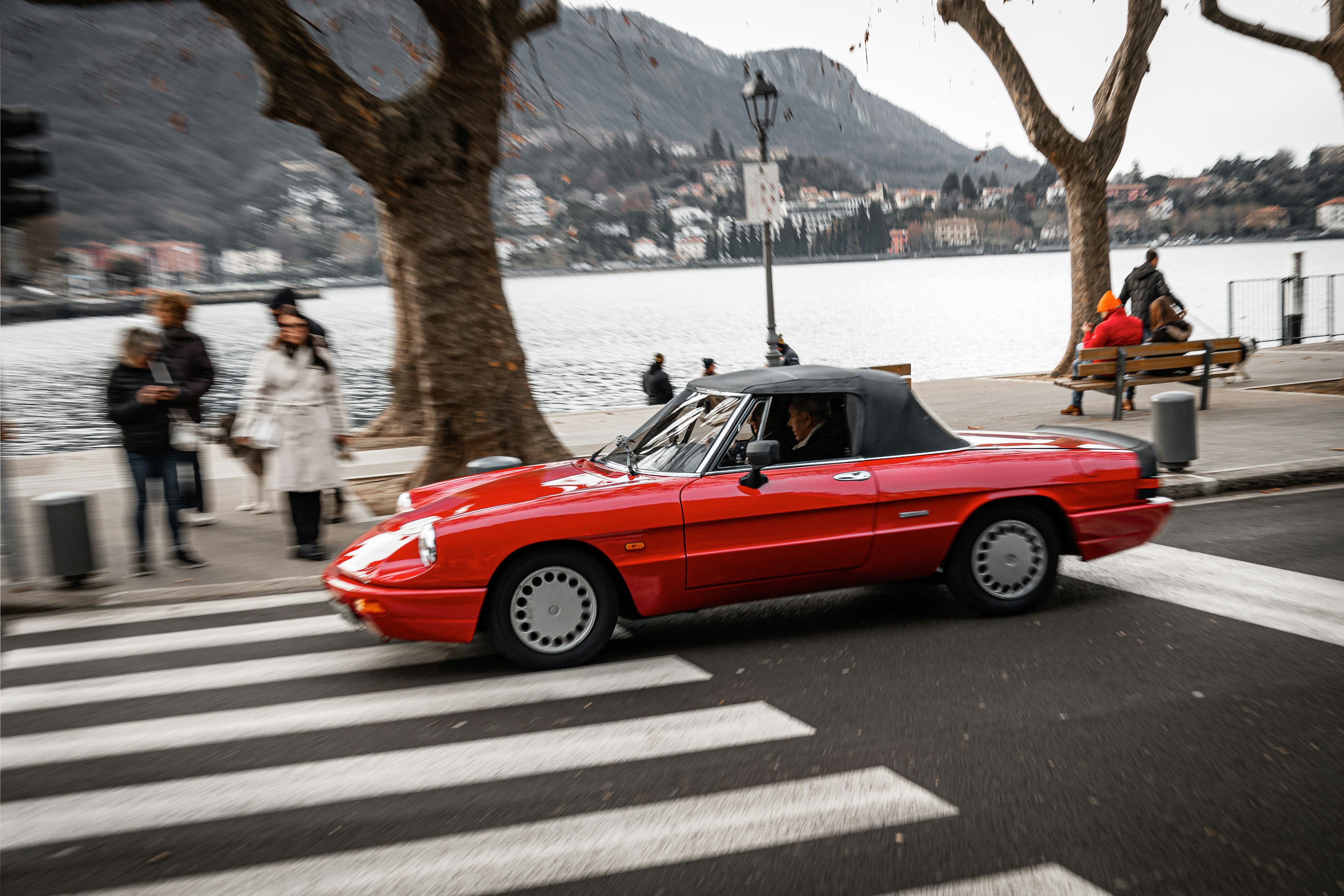 Red Convertible Glides Across a Waterfront Crosswalk