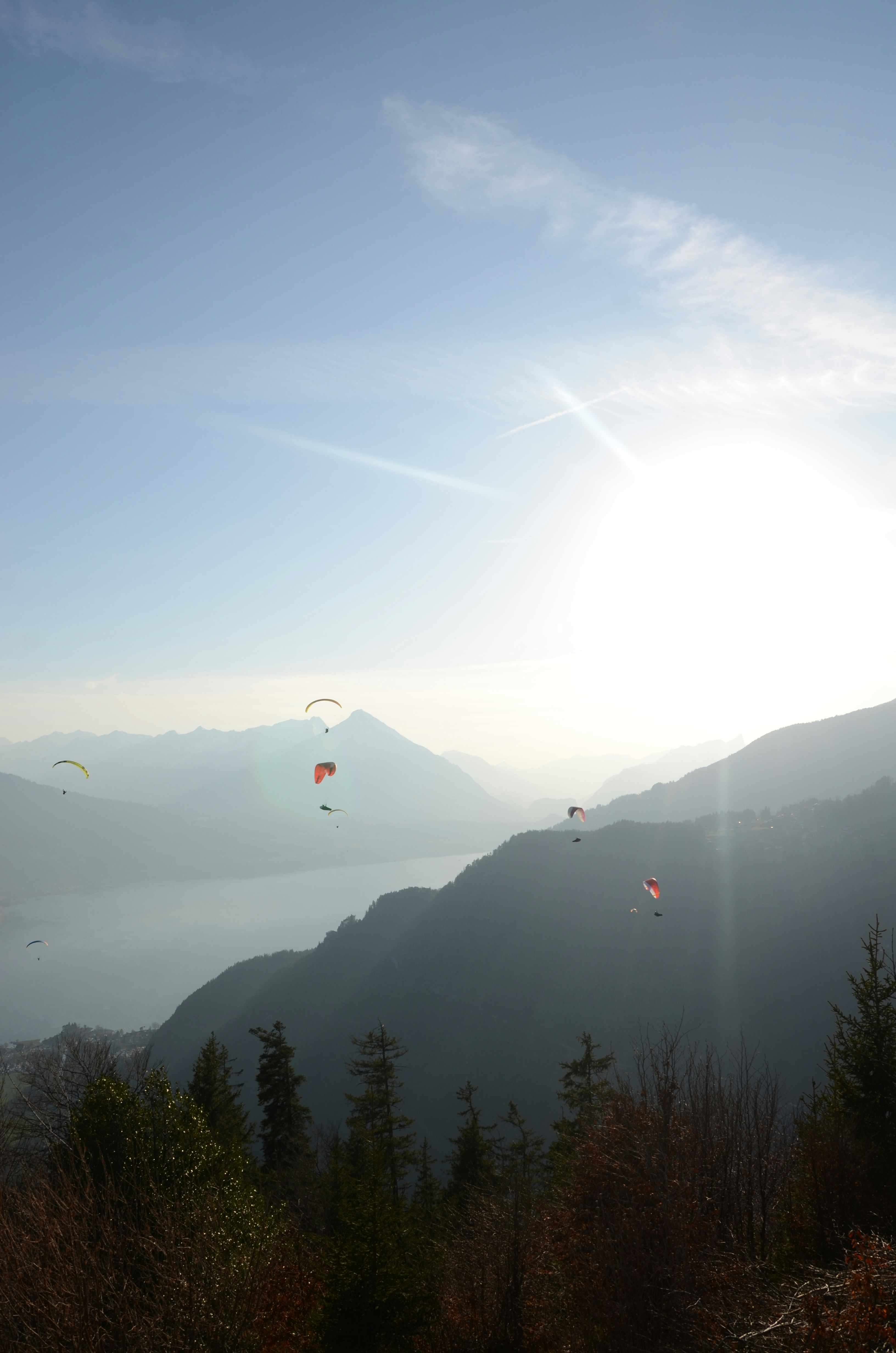 Sunlit Ridge: Paragliders Over a Serene Alpine Lake