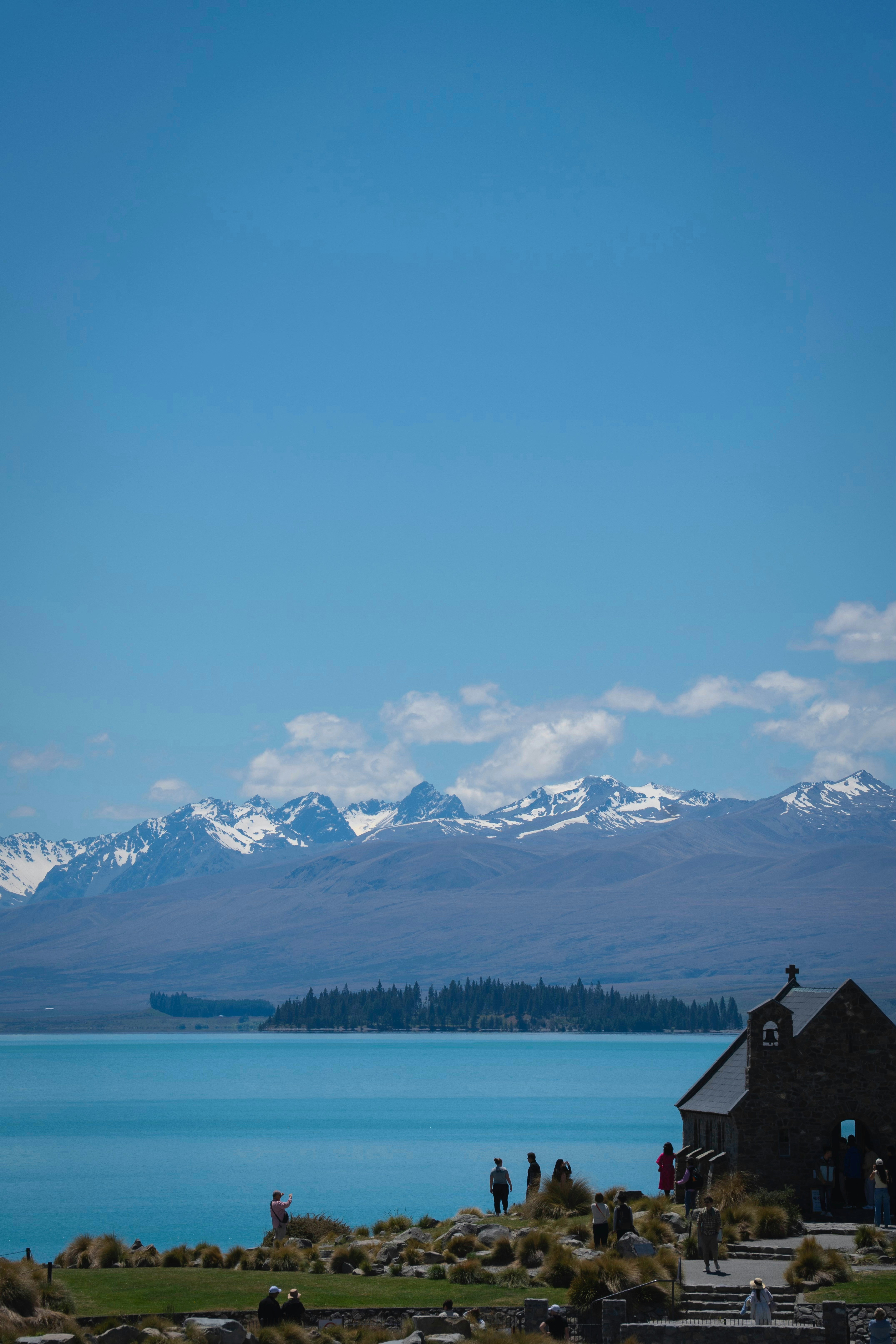 Snow-capped Ridge by a tranquil blue lake with a small riverside church