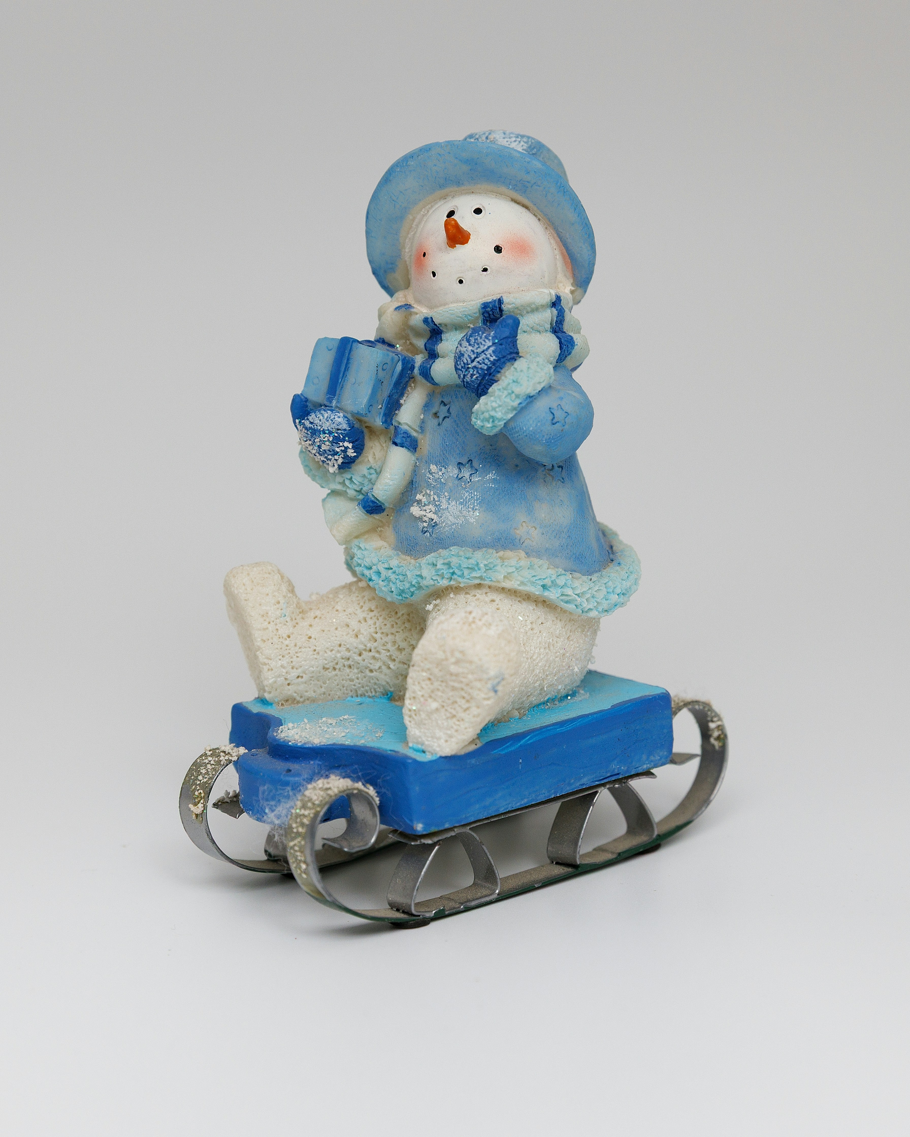 Winter Charm on a Snowy Sled: Snowman Figurine in Blue Parade