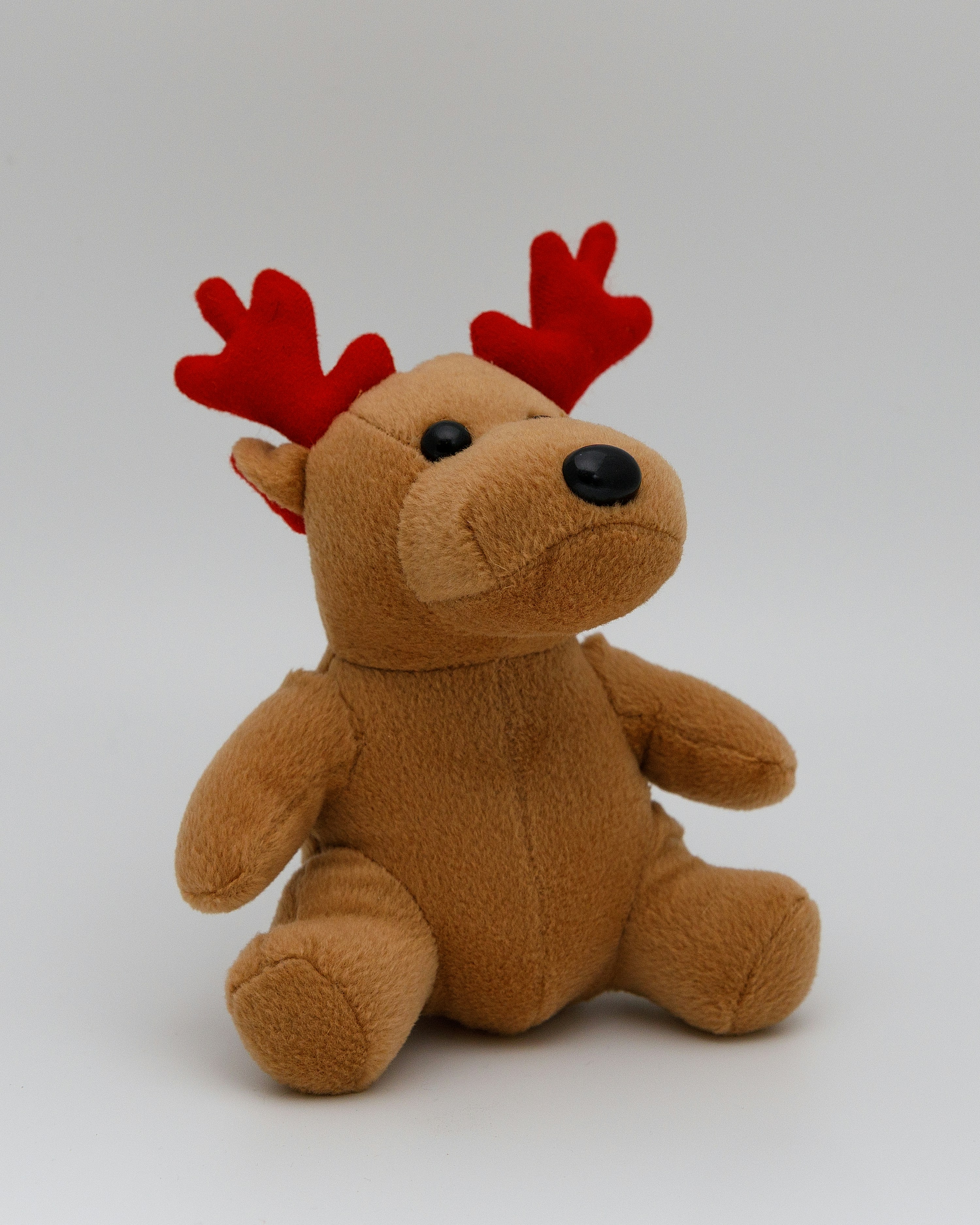 A plush brown reindeer with red antlers.