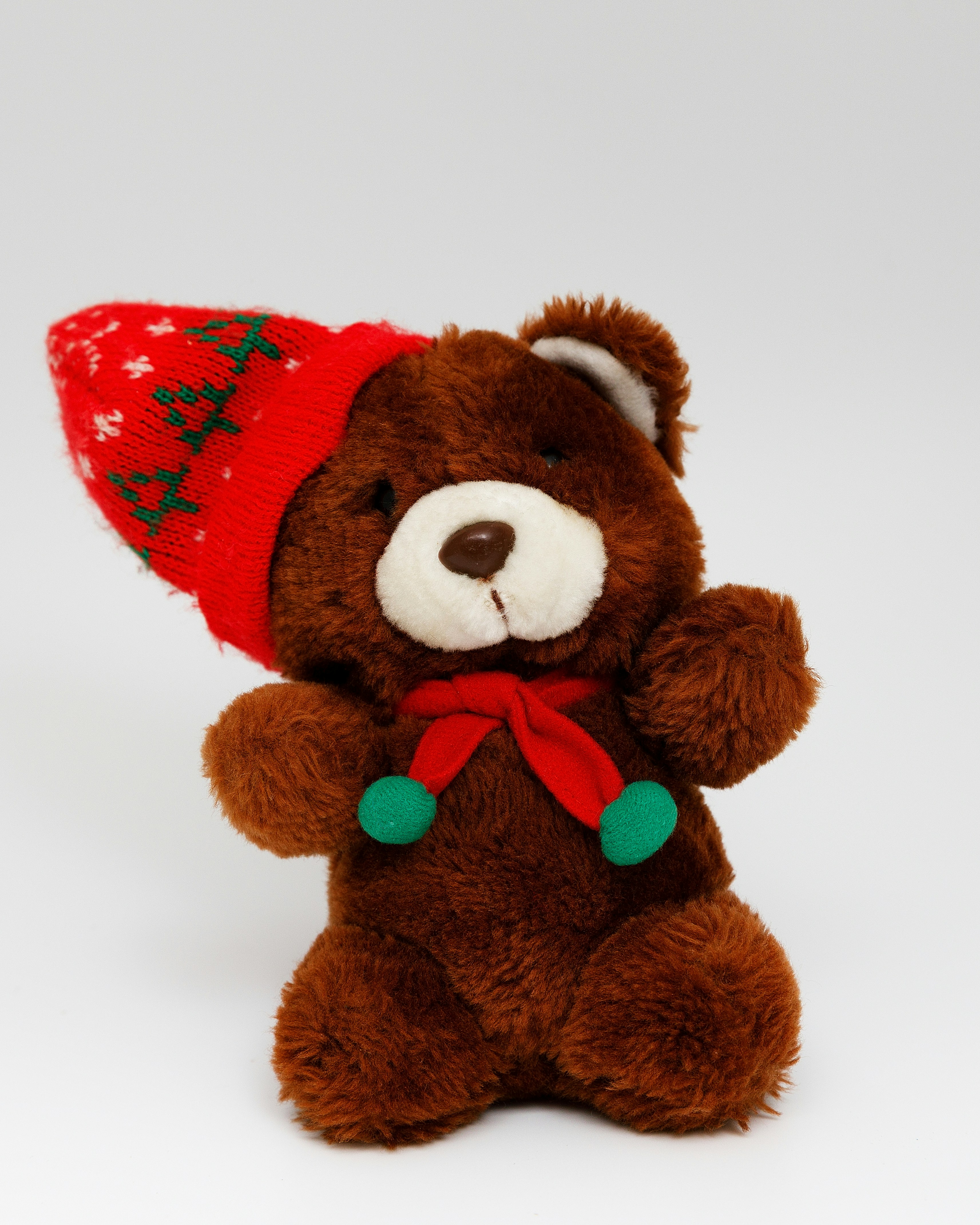 A plush brown bear wearing a red hat.