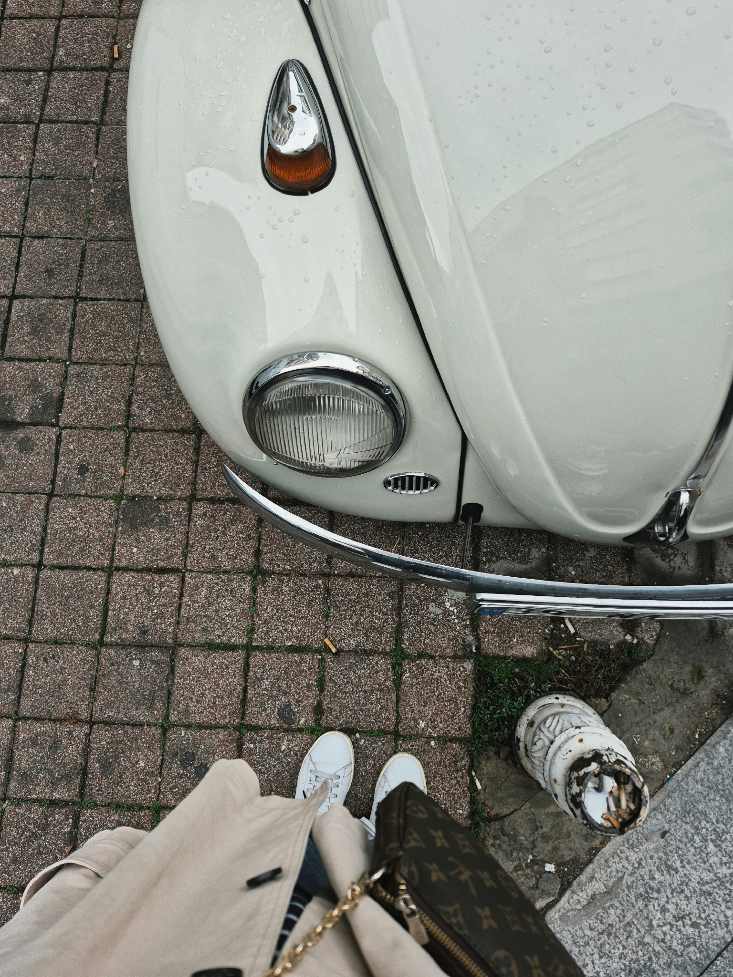 Cream colored vintage car parked on cobblestone street