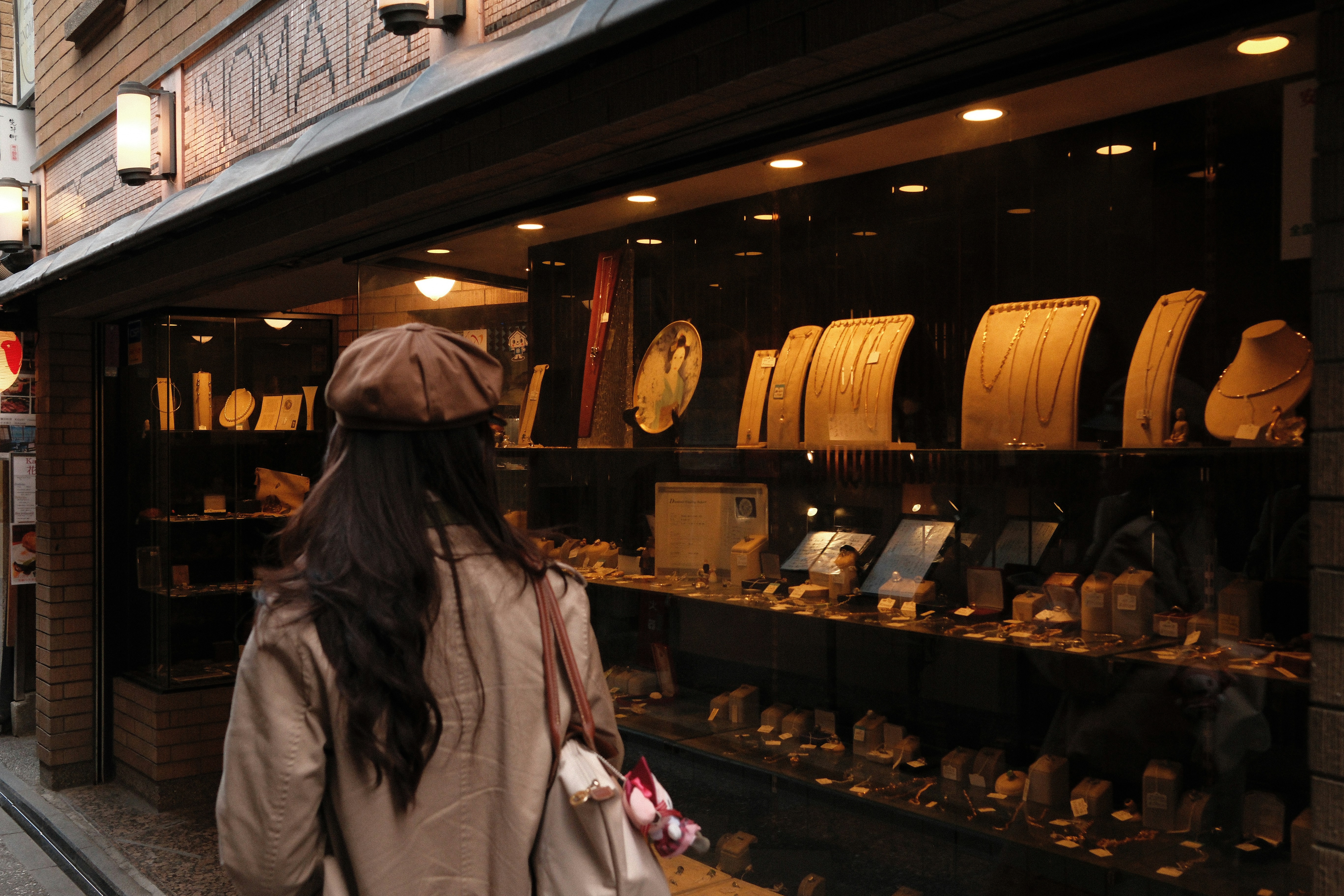 Boutique Street Portrait: A Woman in a Beige Coat Gazes into a Jewelry Store