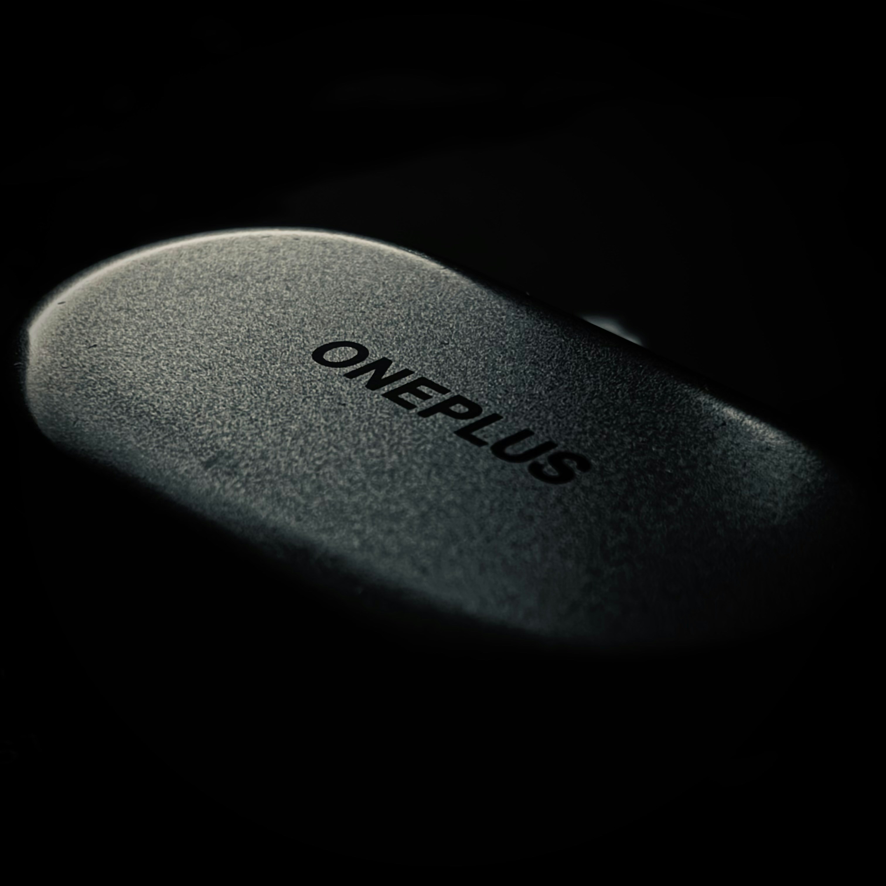 A dark gray oneplus computer mouse on black background