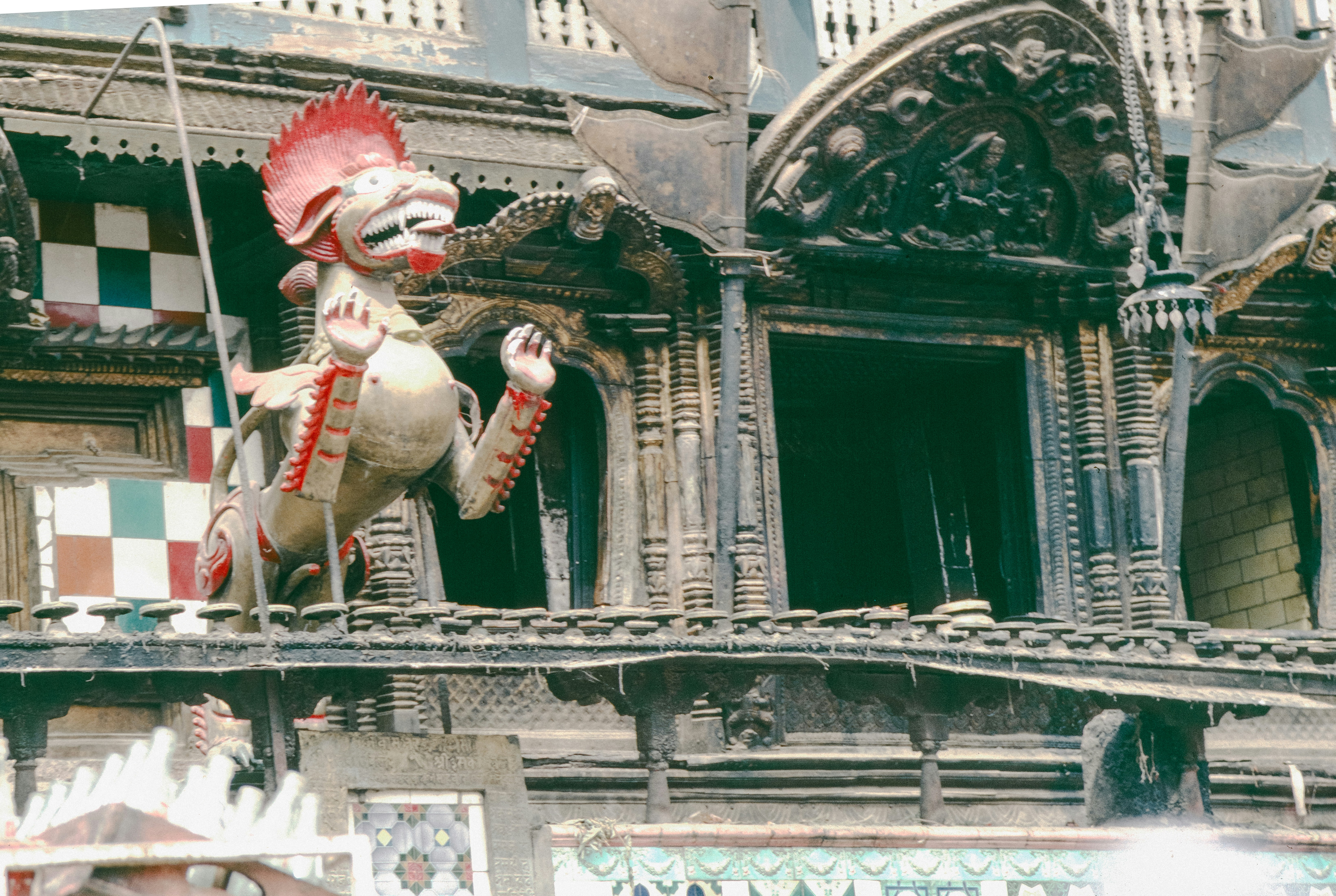Carved temple dragon sentinel peering from an ornate balcony