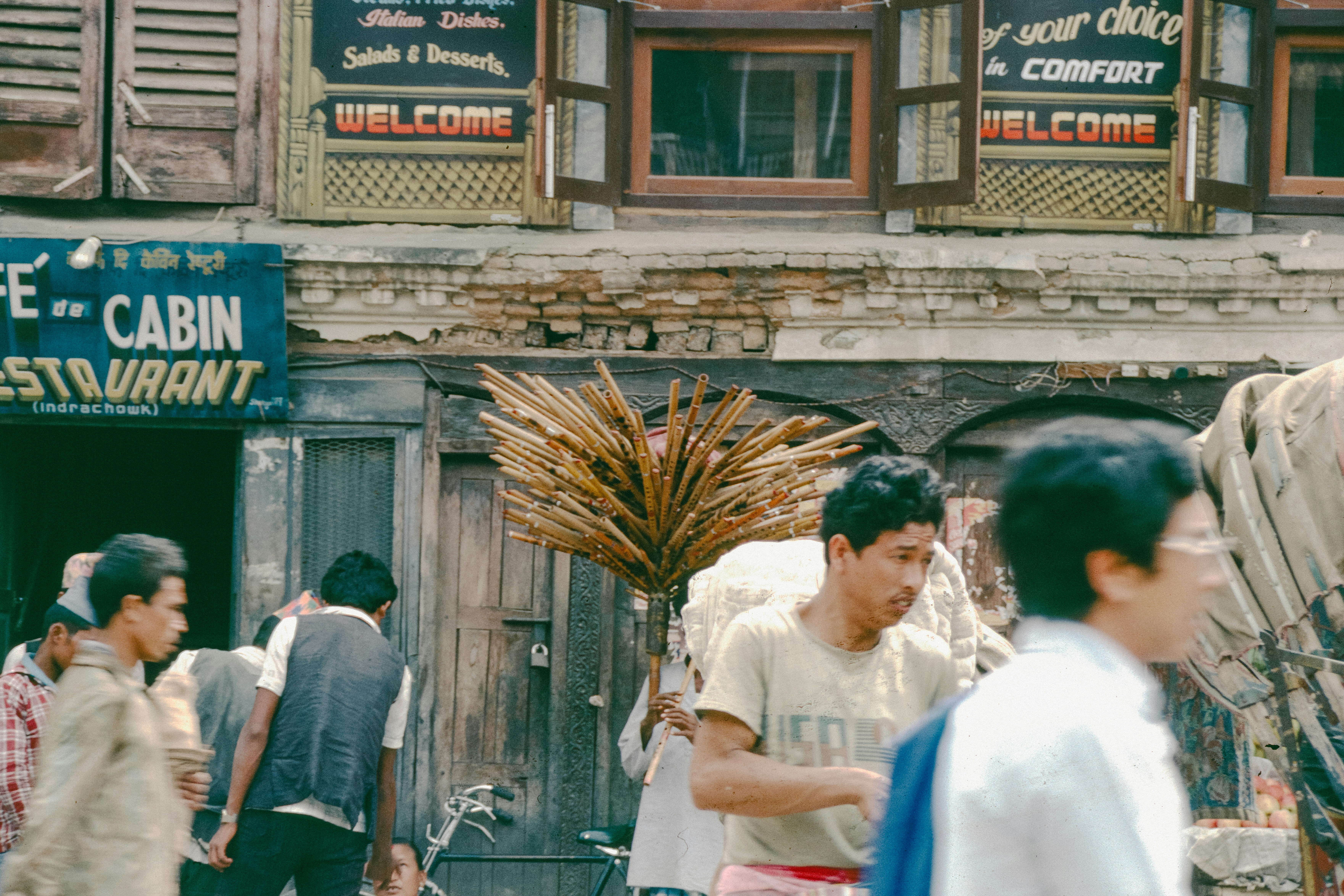 Dusty street scene: travelers bypass a weathered lodge beneath a chipped wooden facade
