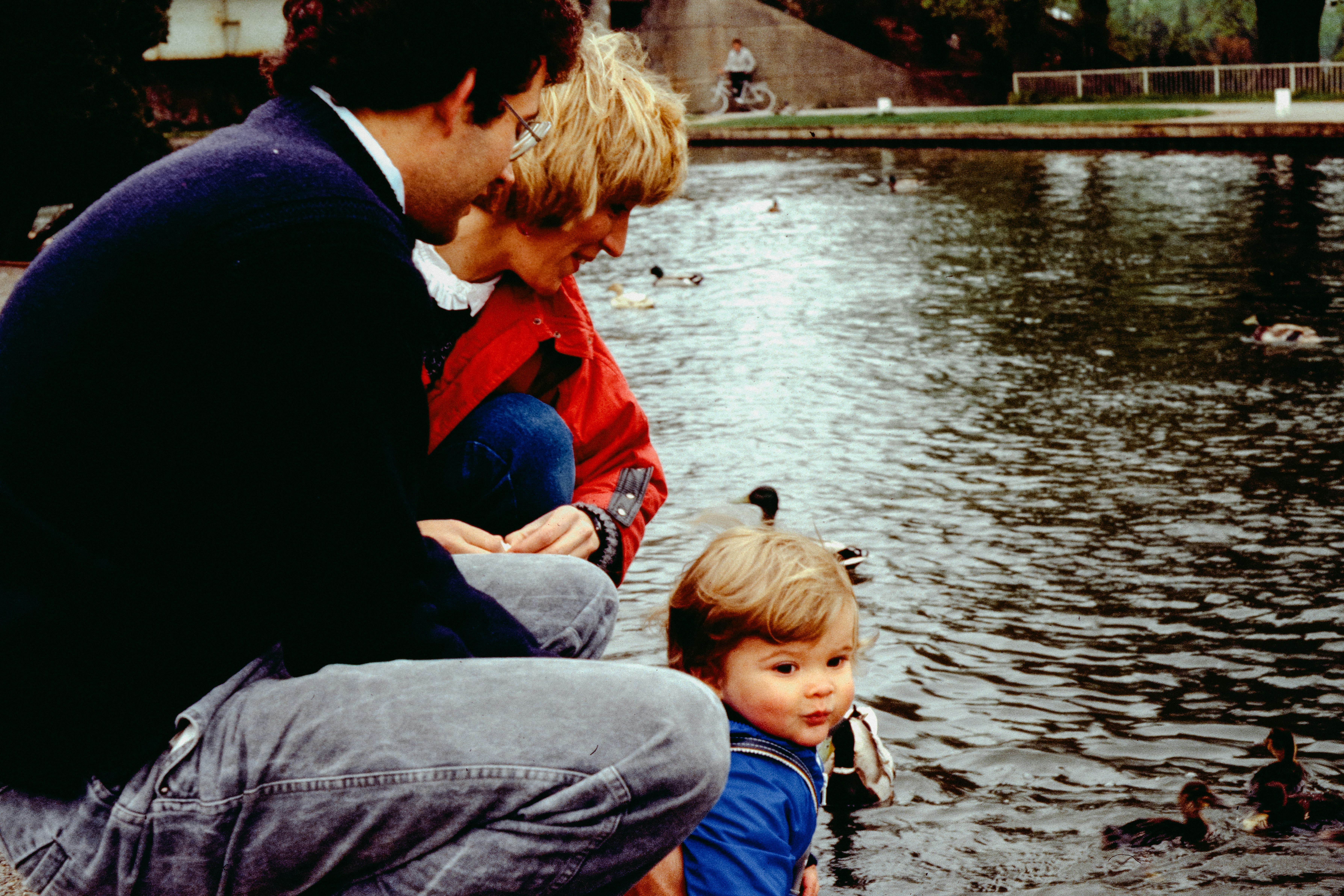 Family by the Pond: A Tender Moment with a Curious Toddler